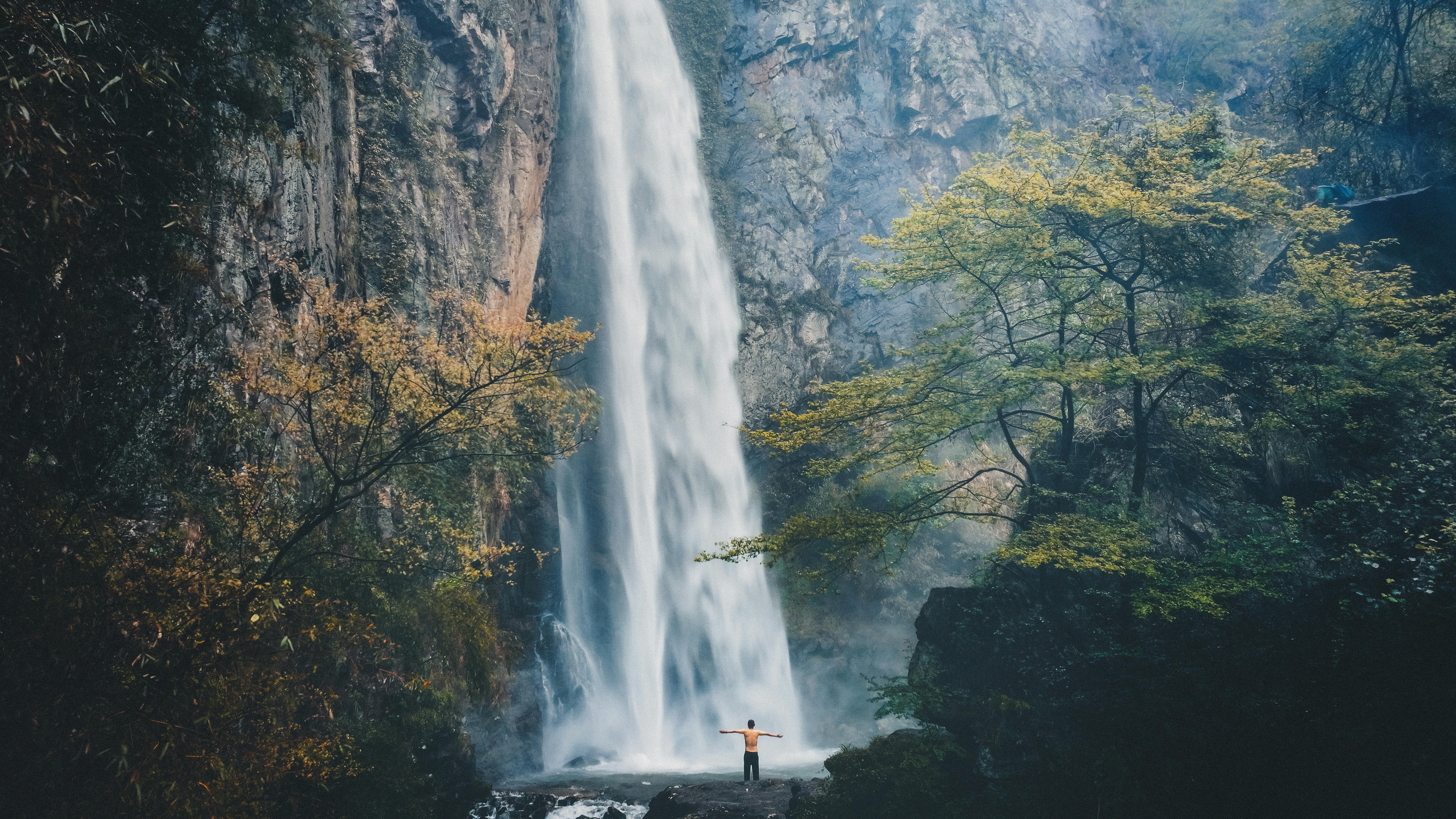 Man Standing under Monumental Waterfall · Free Stock Photo