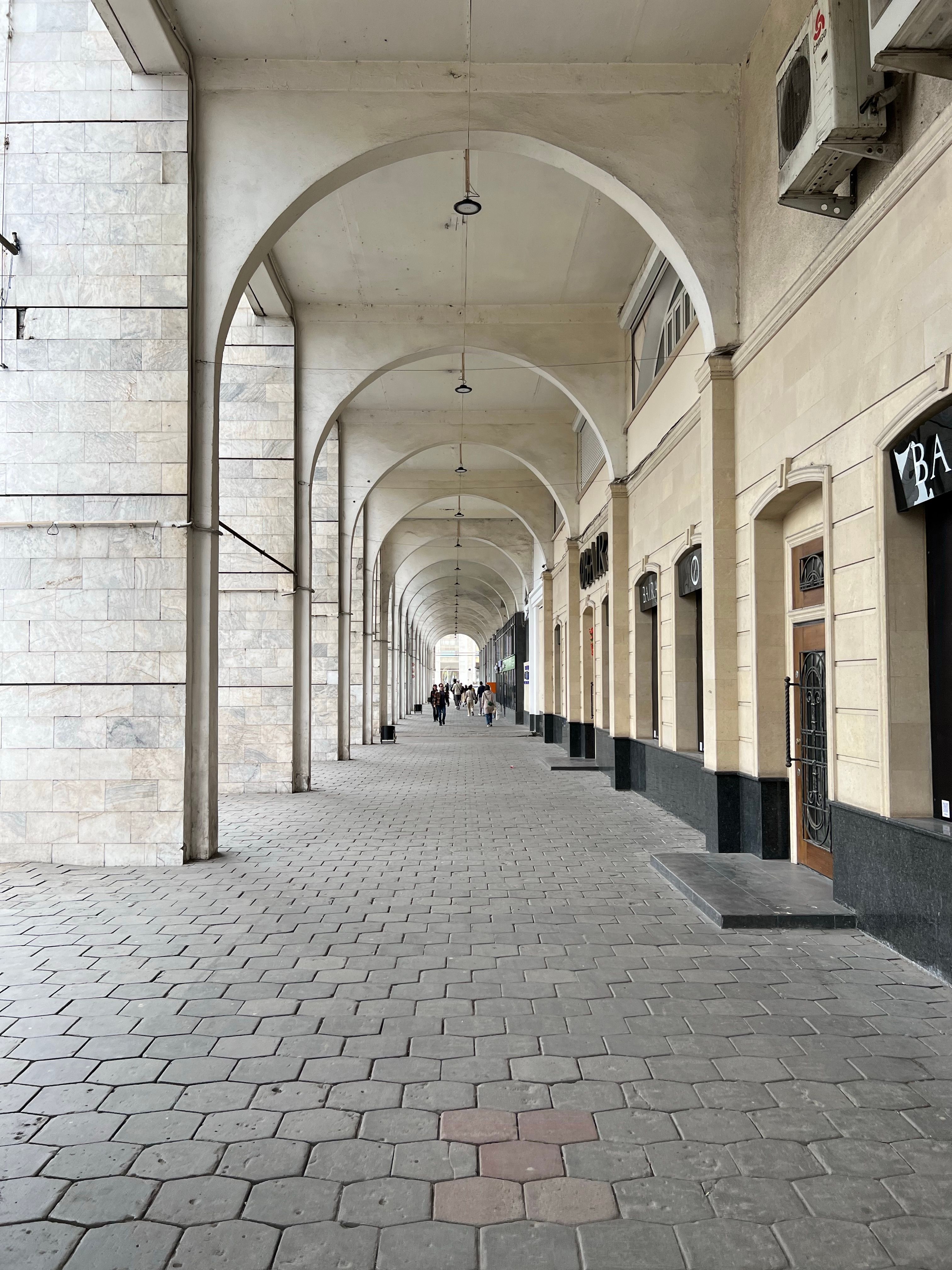 A long walkway with arches and pillars · Free Stock Photo