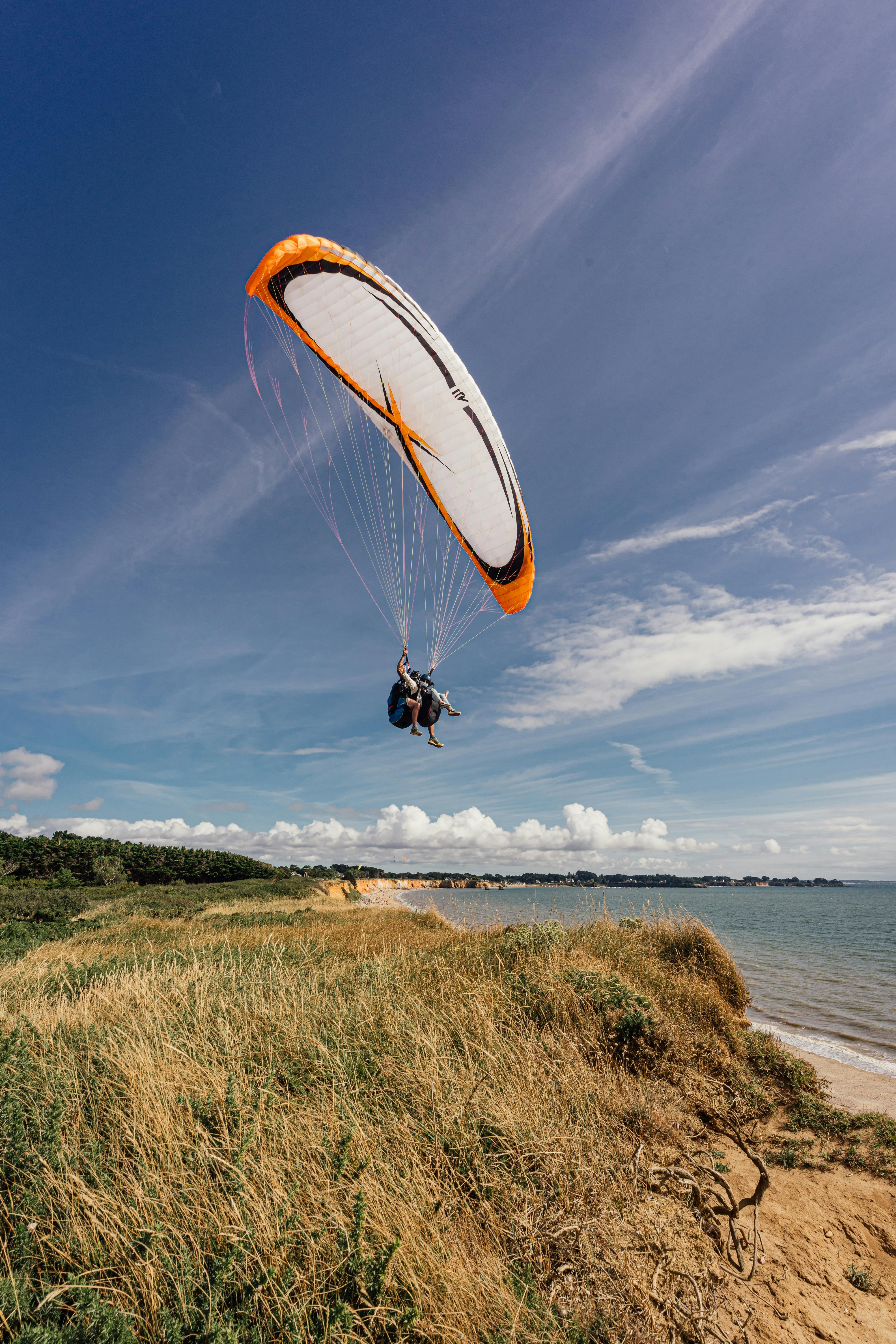 Couple Parachuting on Sea Coast · Free Stock Photo