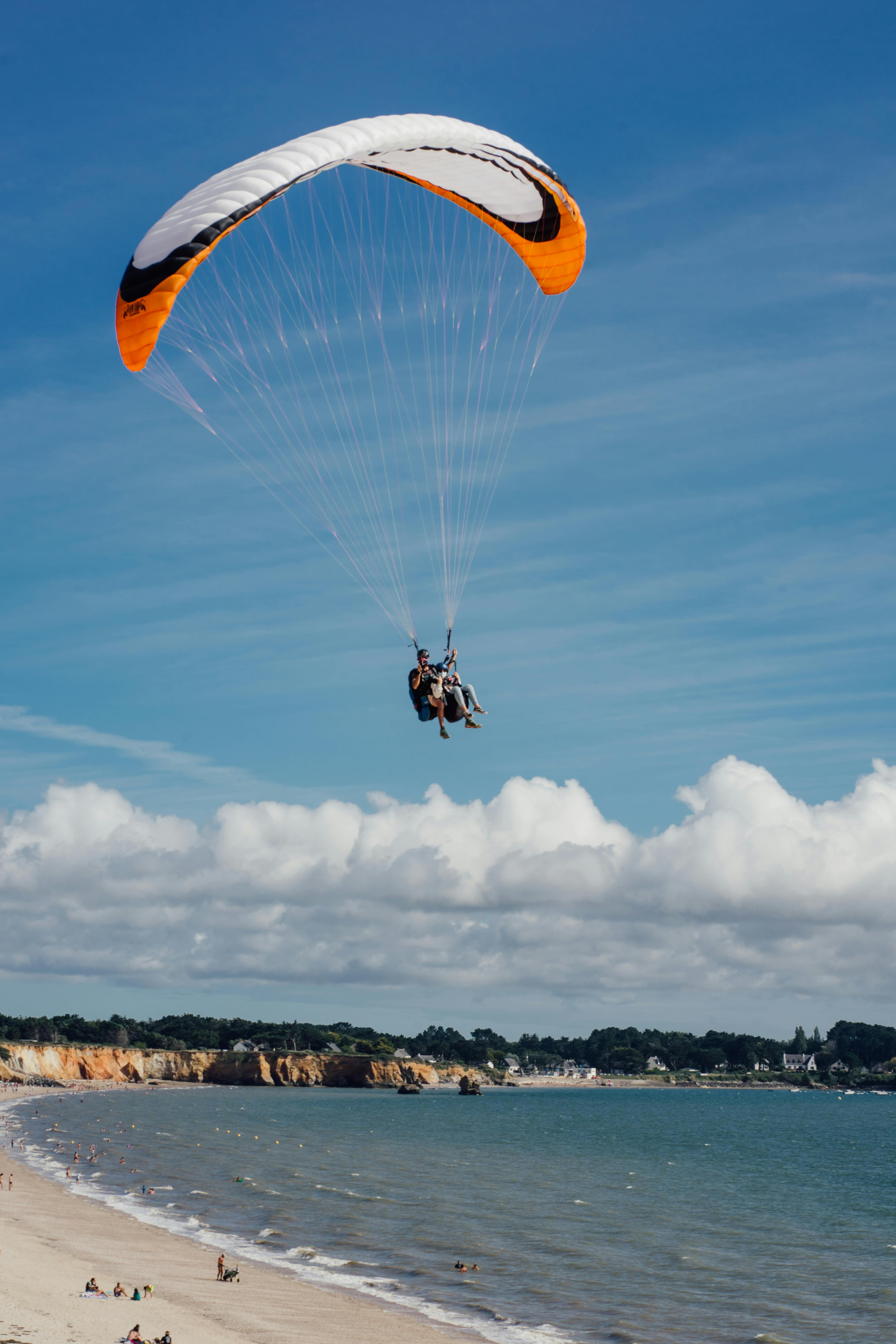 Couple Parachuting on Sea Coast · Free Stock Photo