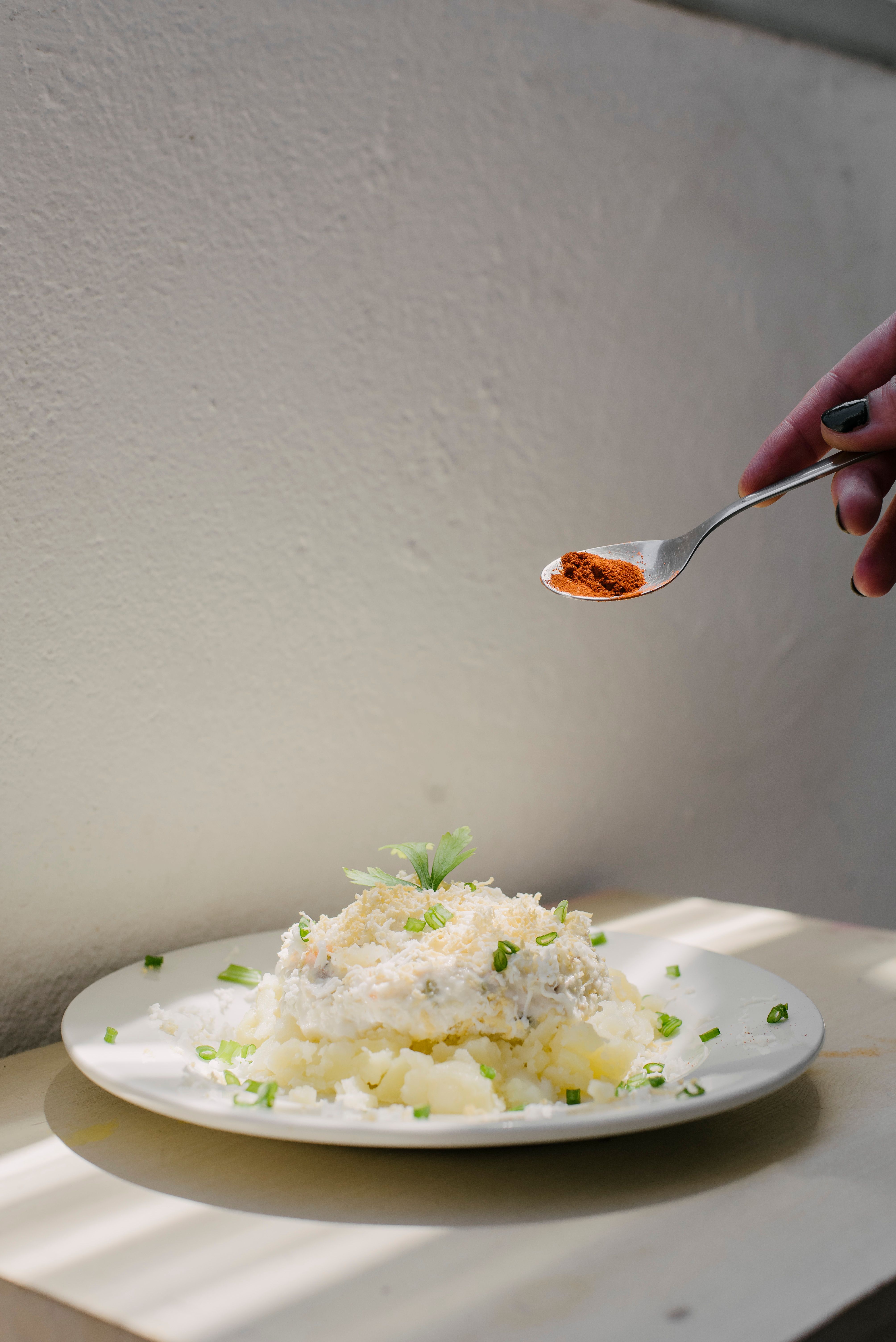 A person holding a spoon over a plate of food · Free Stock Photo