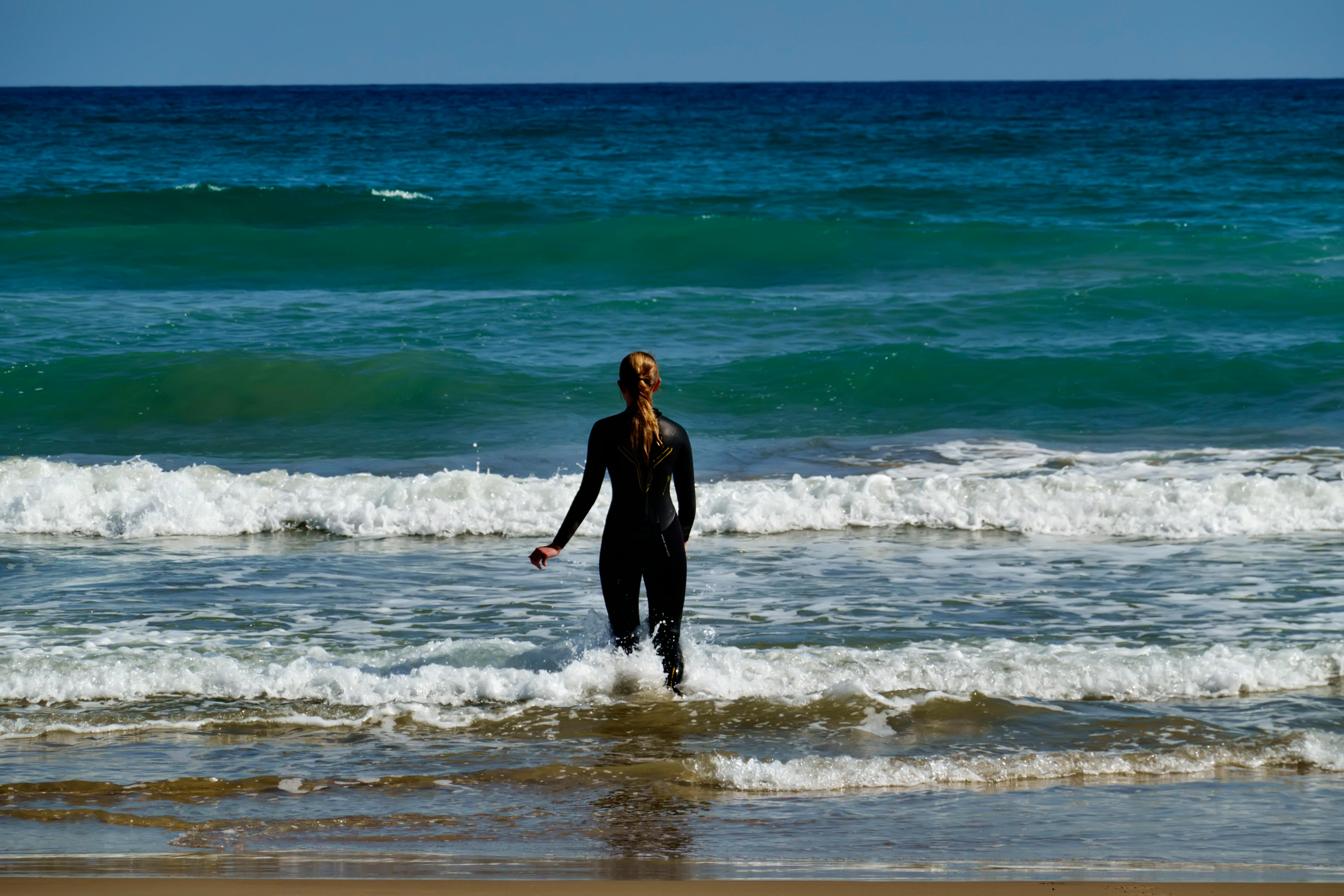 Woman in Wetsuit Walking into Sea · Free Stock Photo