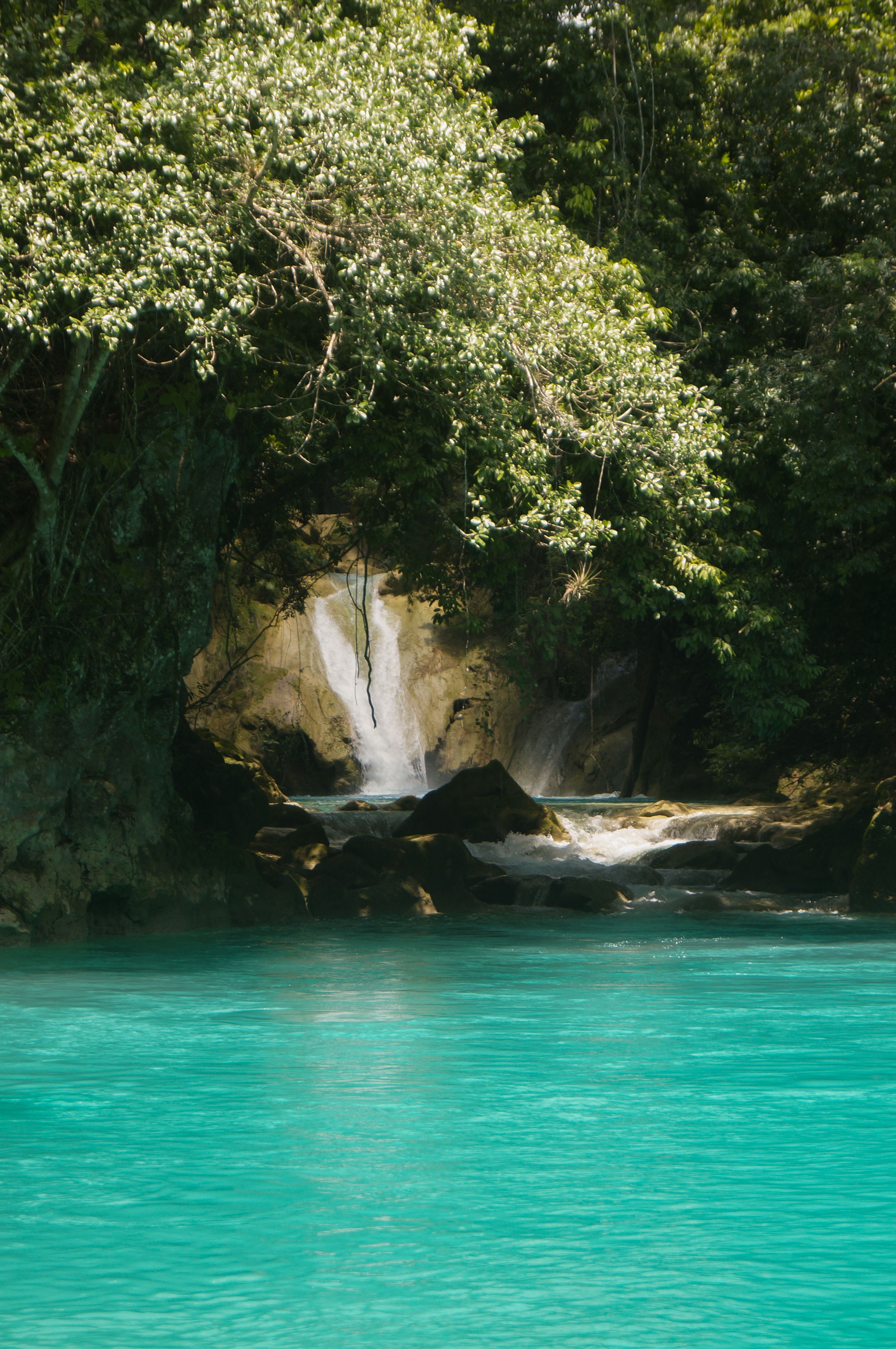 A waterfall in the middle of a turquoise blue lake · Free Stock Photo