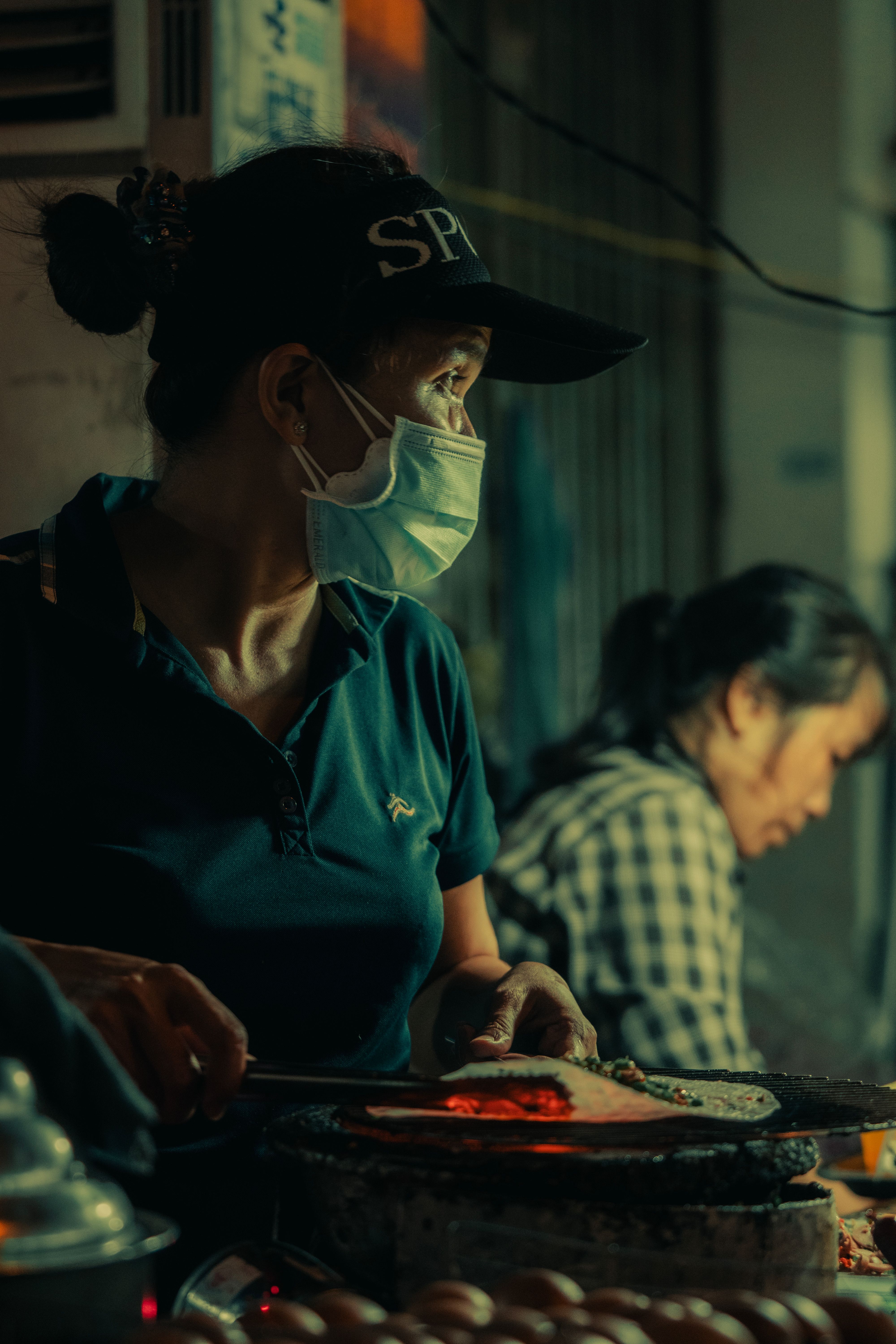Cook Wearing Two Face Masks Cooking at a Street Stall · Free Stock Photo