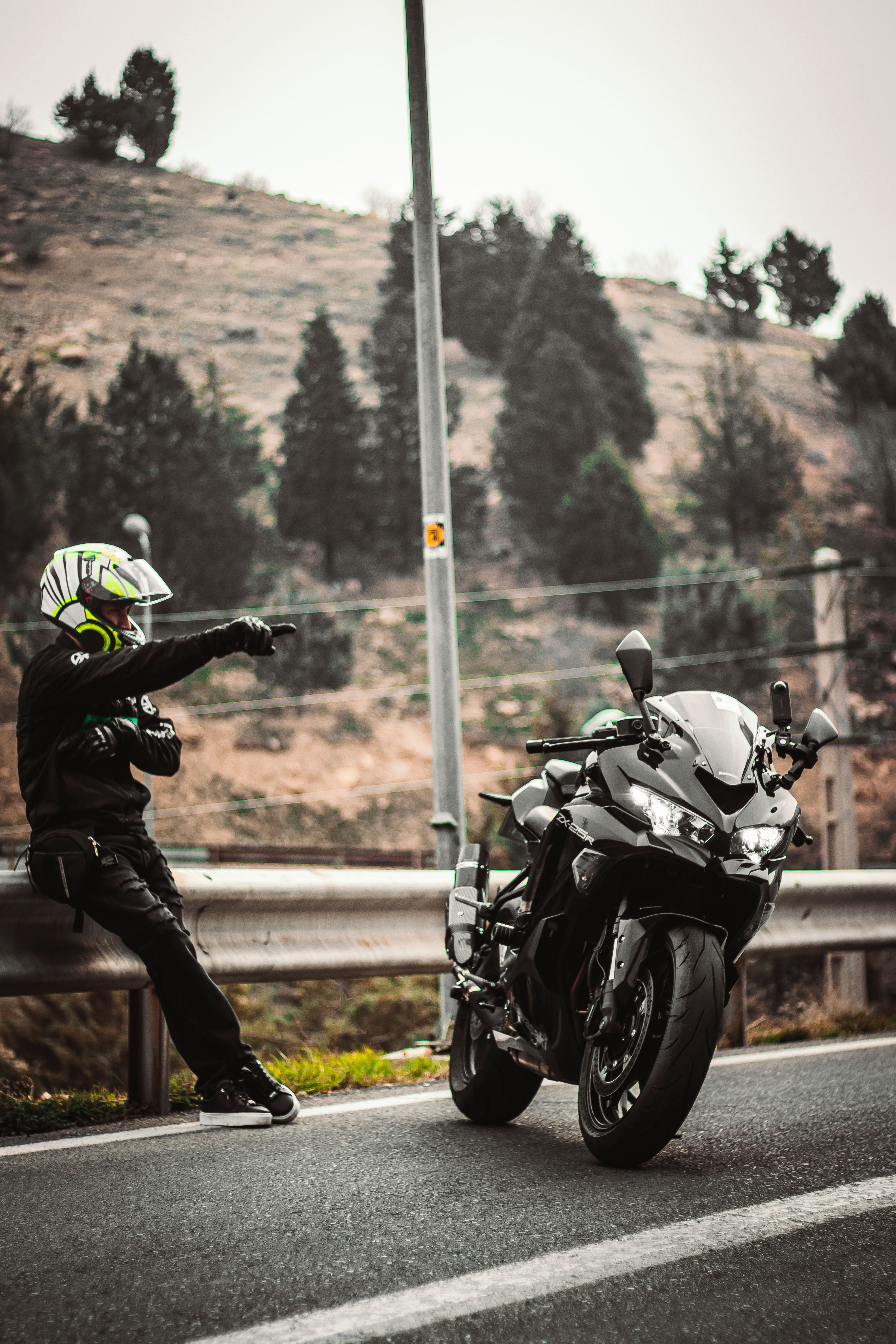 Motorcyclist Sitting on Road Barrier Close to Black Motorcycle · Free ...