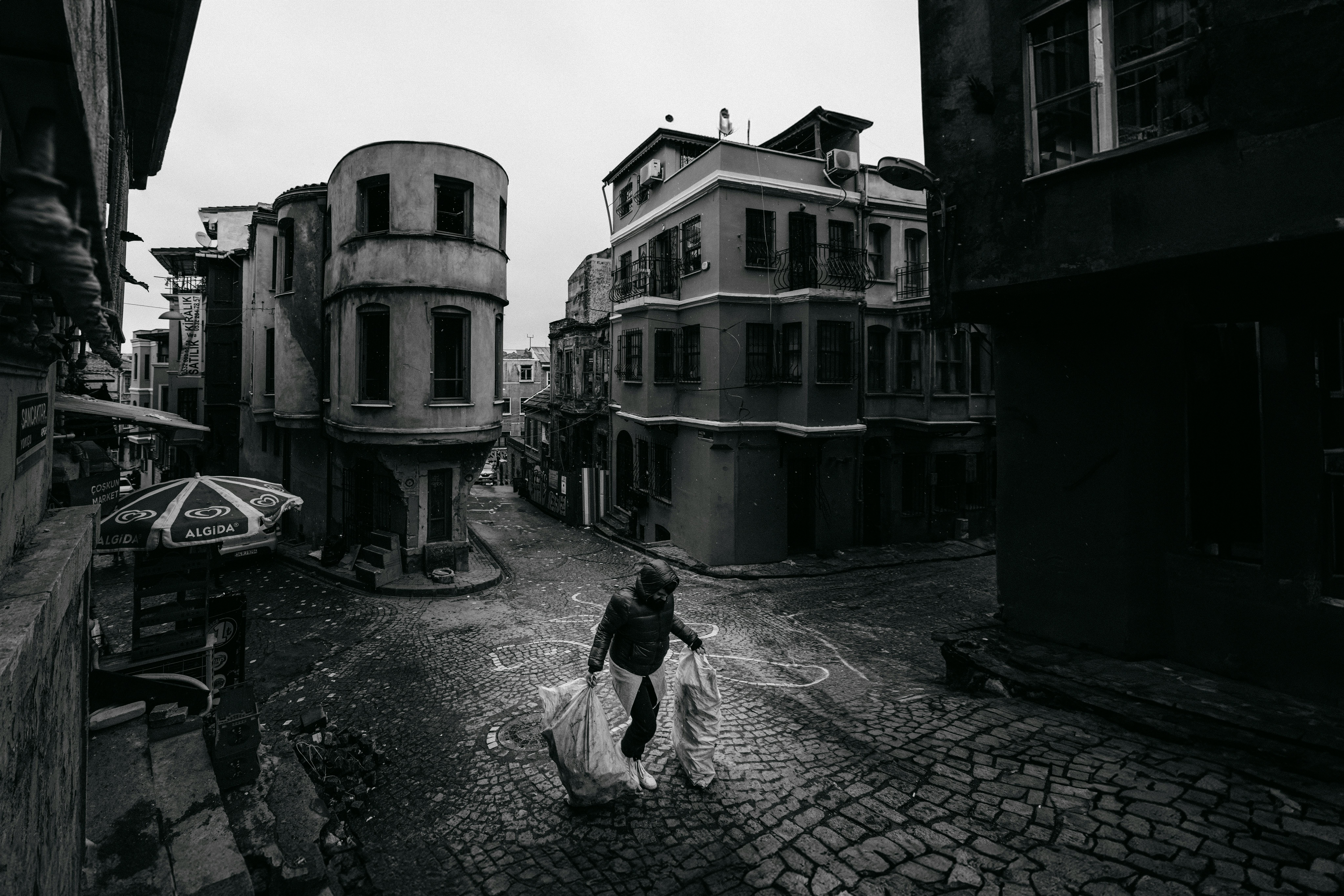 Black and White Photo of a Pedestrian Walking Alone on a Cobblestone ...