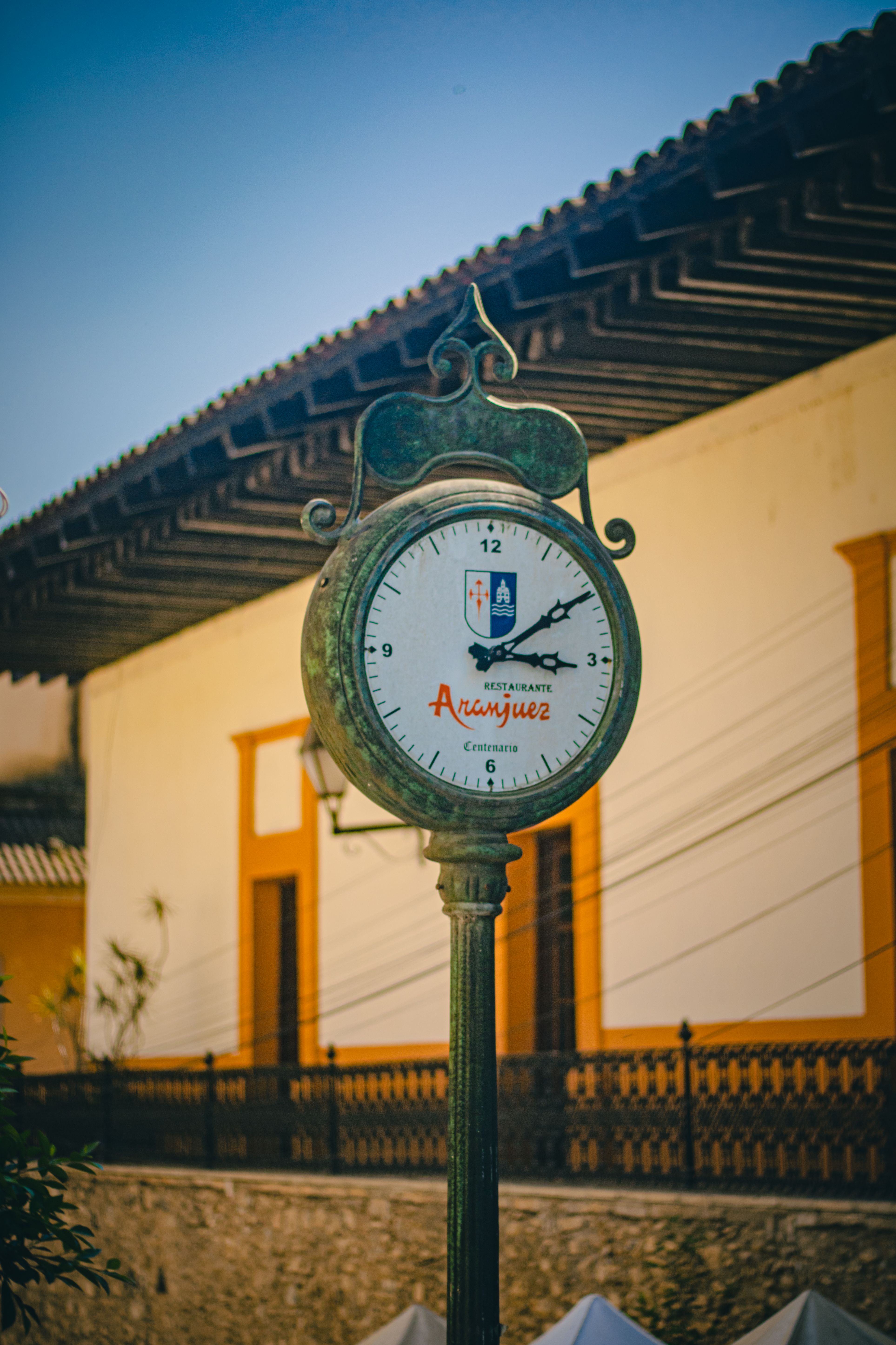 A clock on the side of a building with a white roof · Free Stock Photo