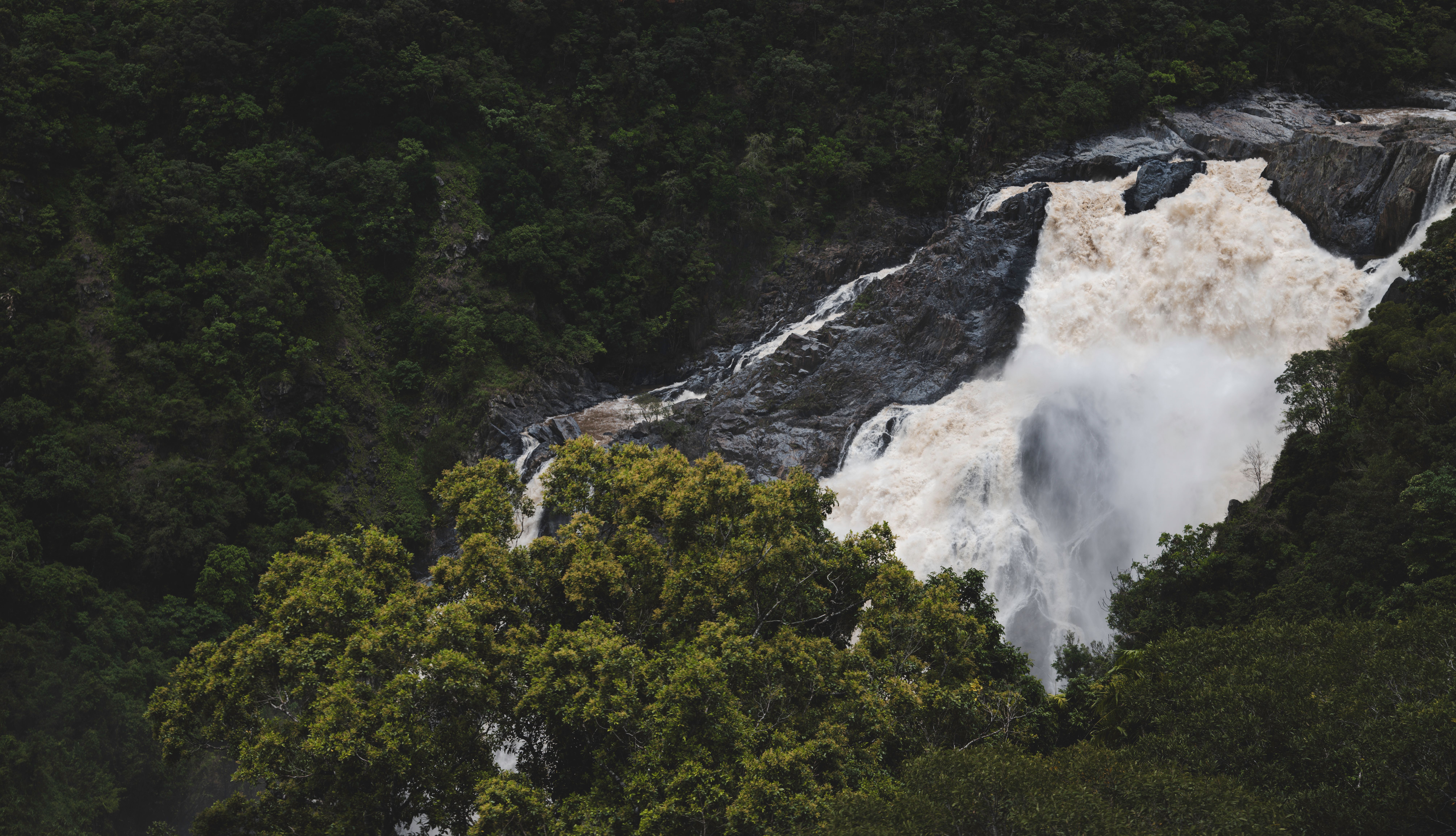 A helicopter flying over a waterfall in the jungle · Free Stock Photo