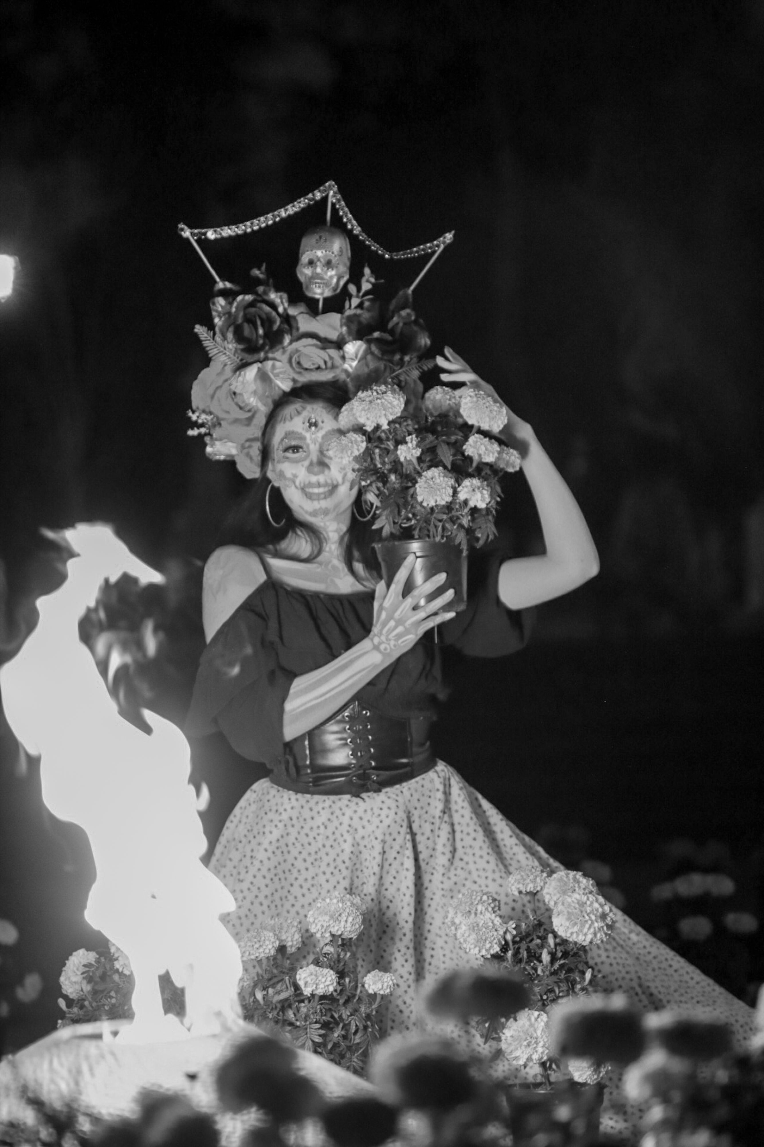 Smiling Catrina Sitting with Flowers near Fire at Night · Free Stock Photo