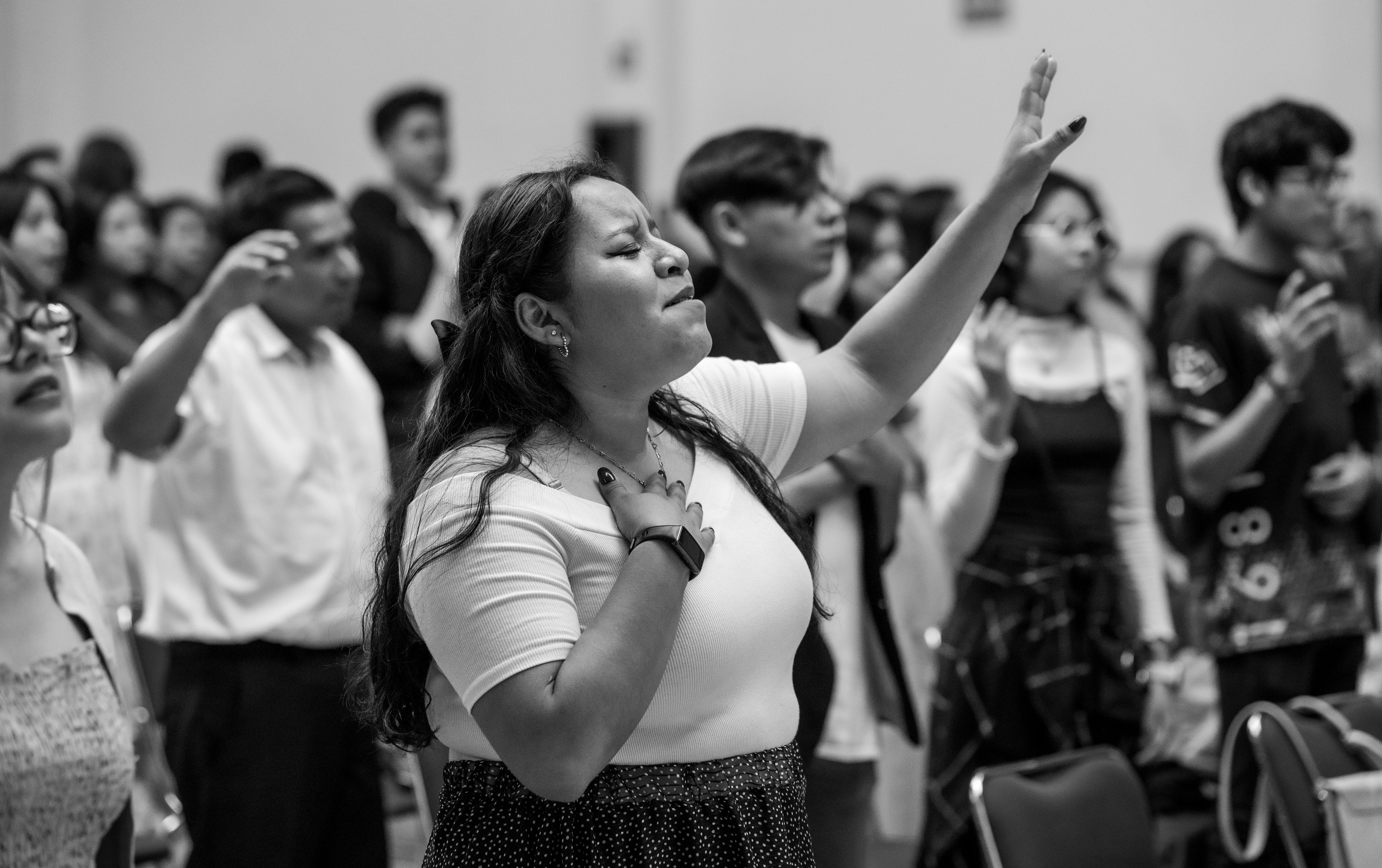 Woman Praying with Arm Raised at Gathering · Free Stock Photo