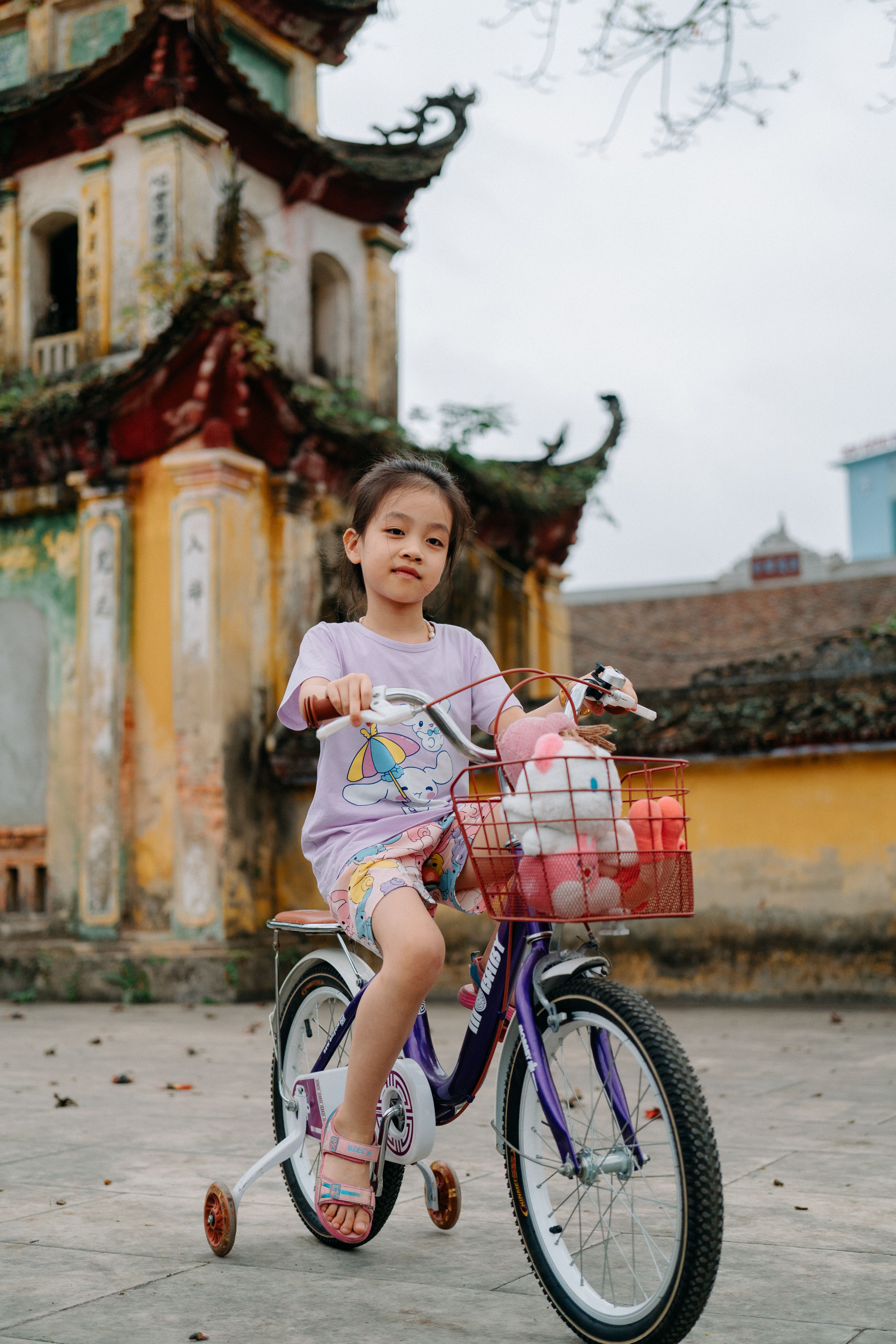 A little girl riding a bike in front of a pagoda · Free Stock Photo