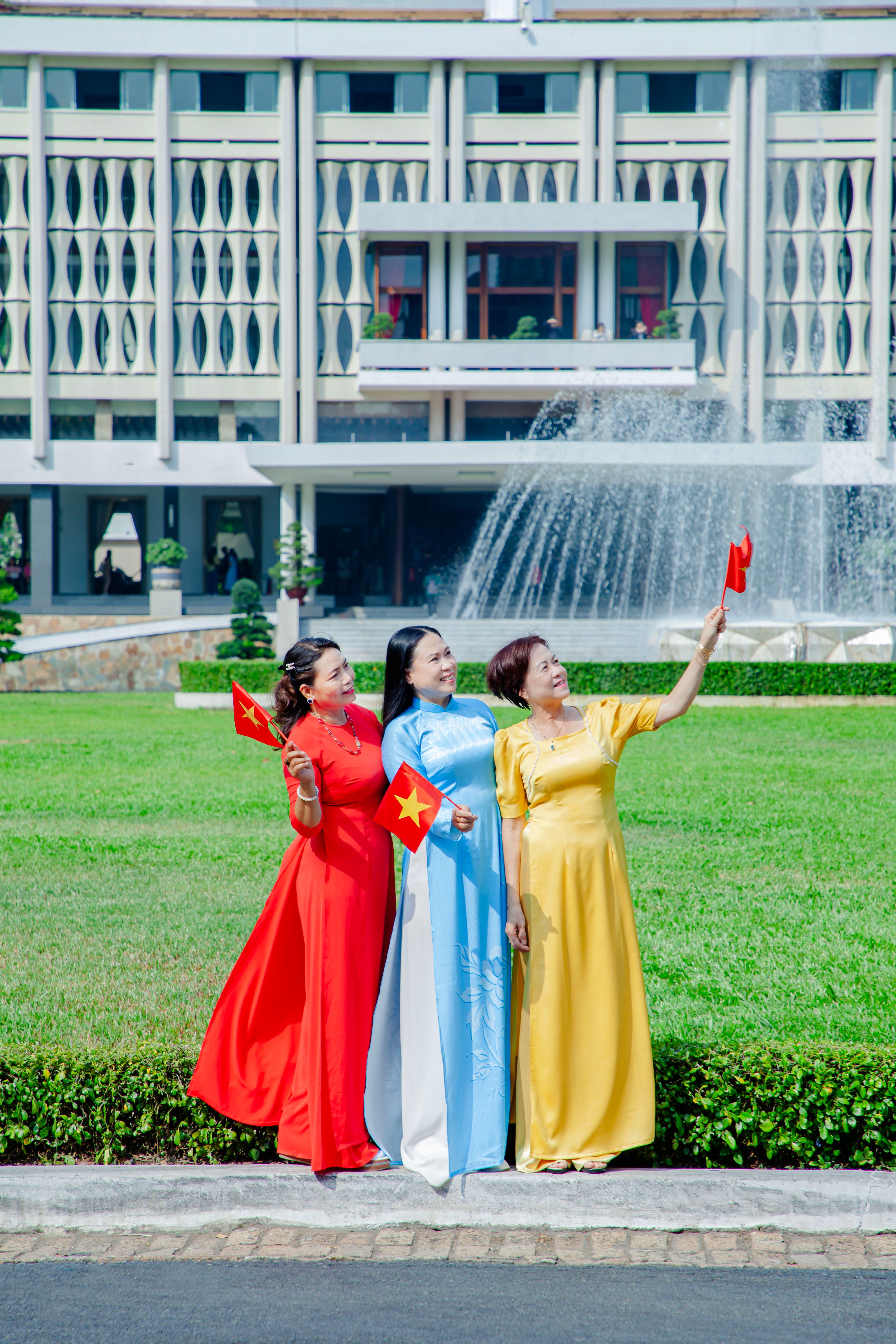 Women in Traditional Dresses Waving Vietnamese Flags in Front of ...