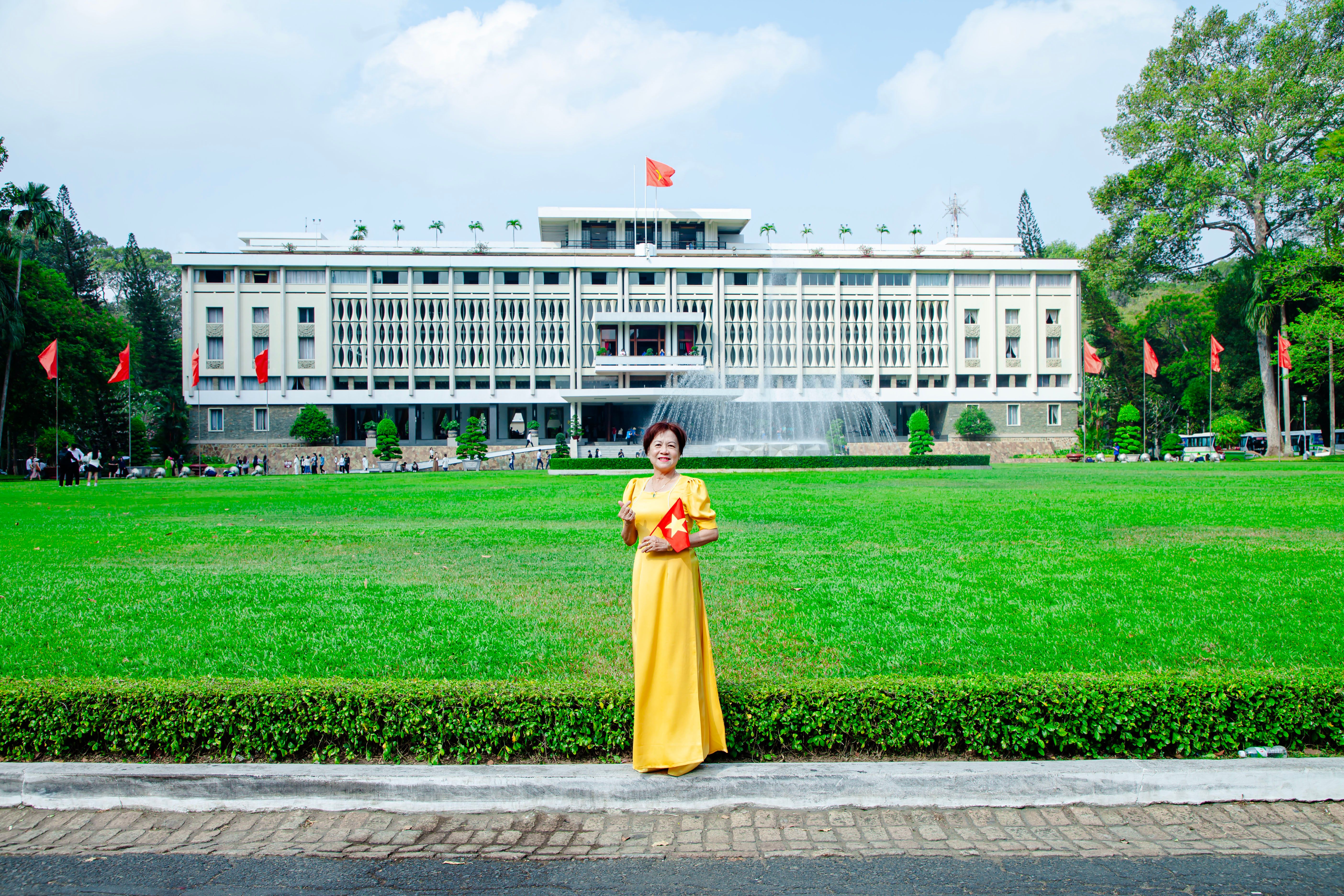 Woman in Yellow Dress and with Flag Standing by Independence Palace in ...