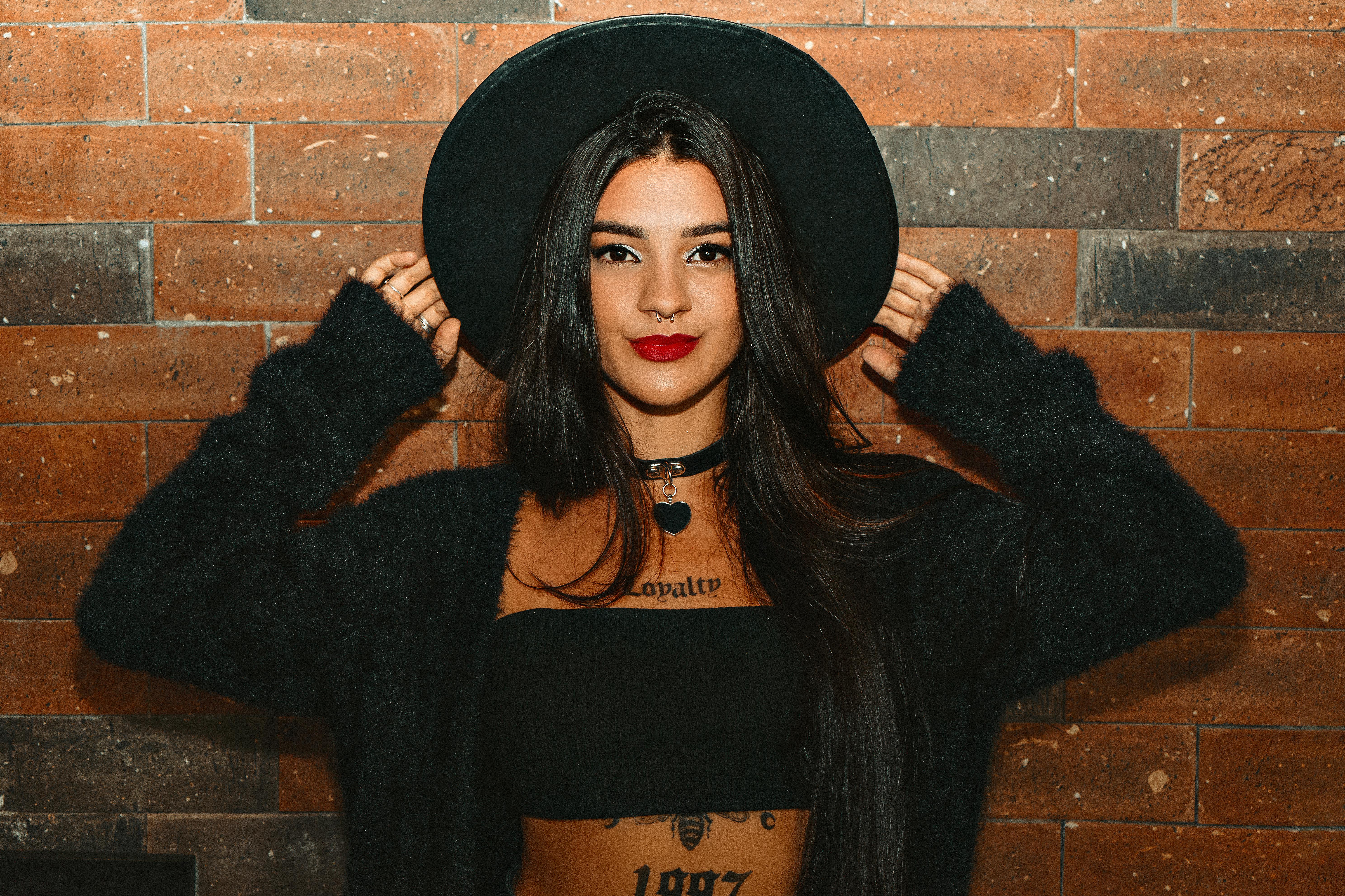 Woman in Black Fixing Hat on her Head · Free Stock Photo