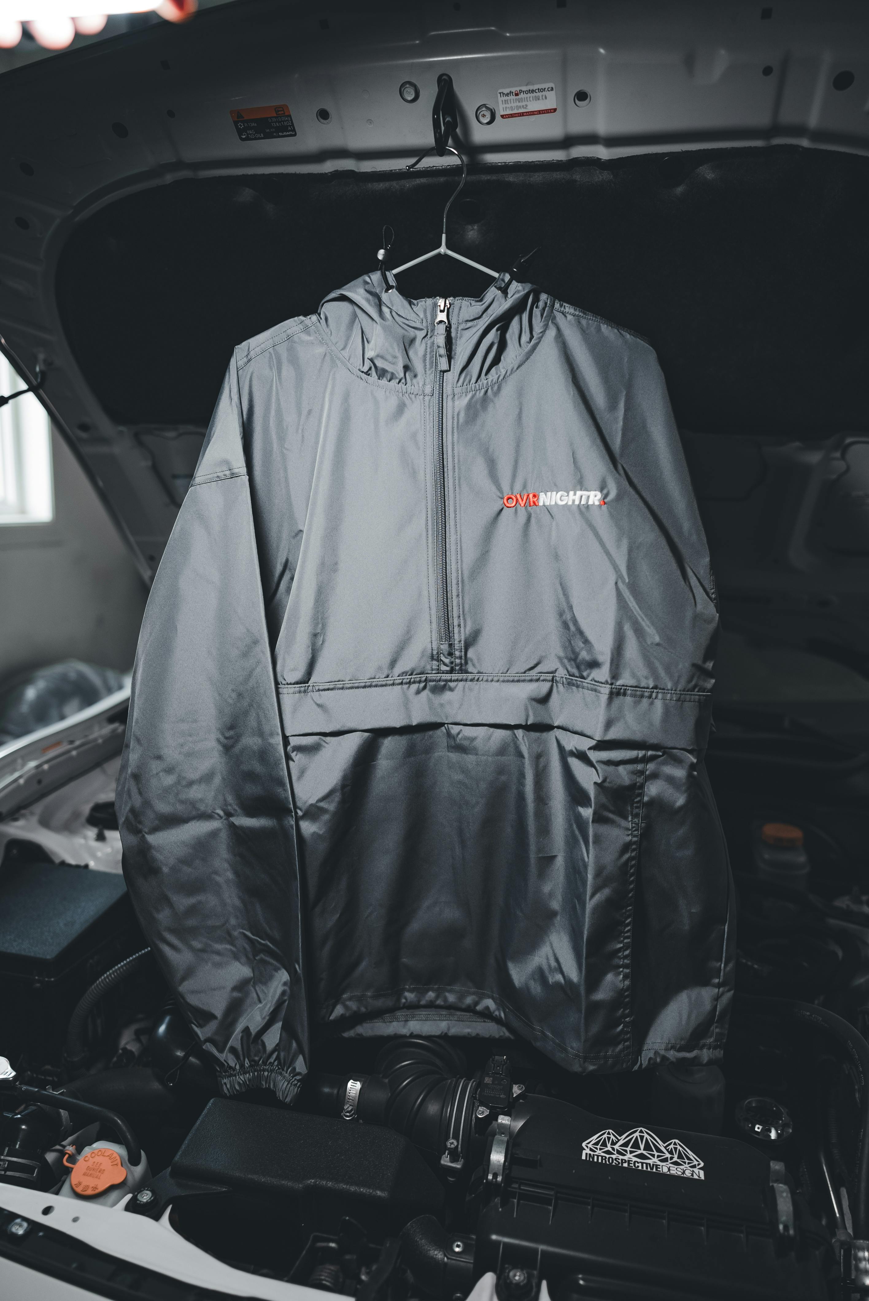 Ovrnigtr Windbreaker Jacket Hanging in a Open Car Hood · Free Stock Photo