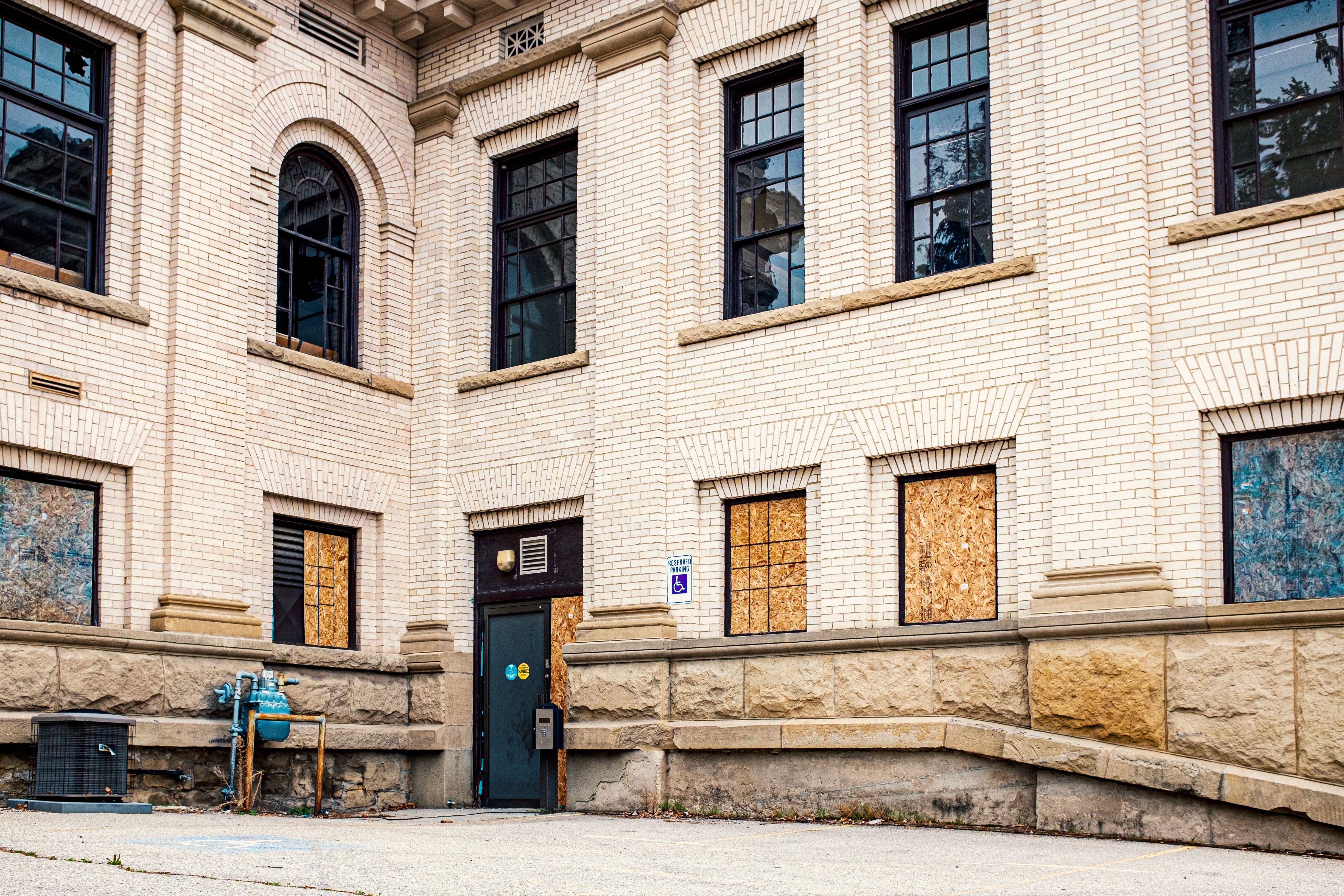 A building with windows boarded up and a sign that says, 'closed ...