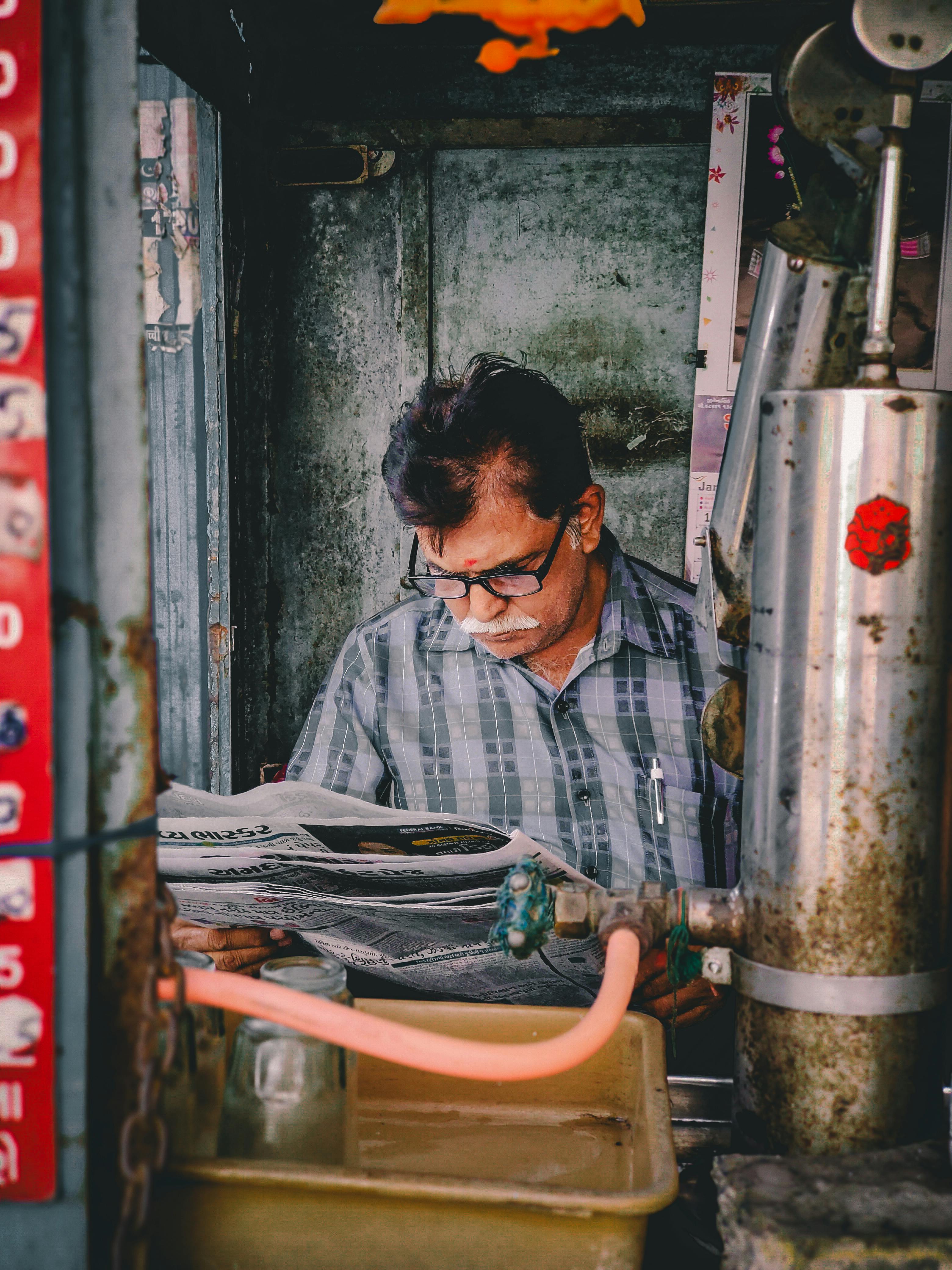 Man Reading a Newspaper in a Booth · Free Stock Photo