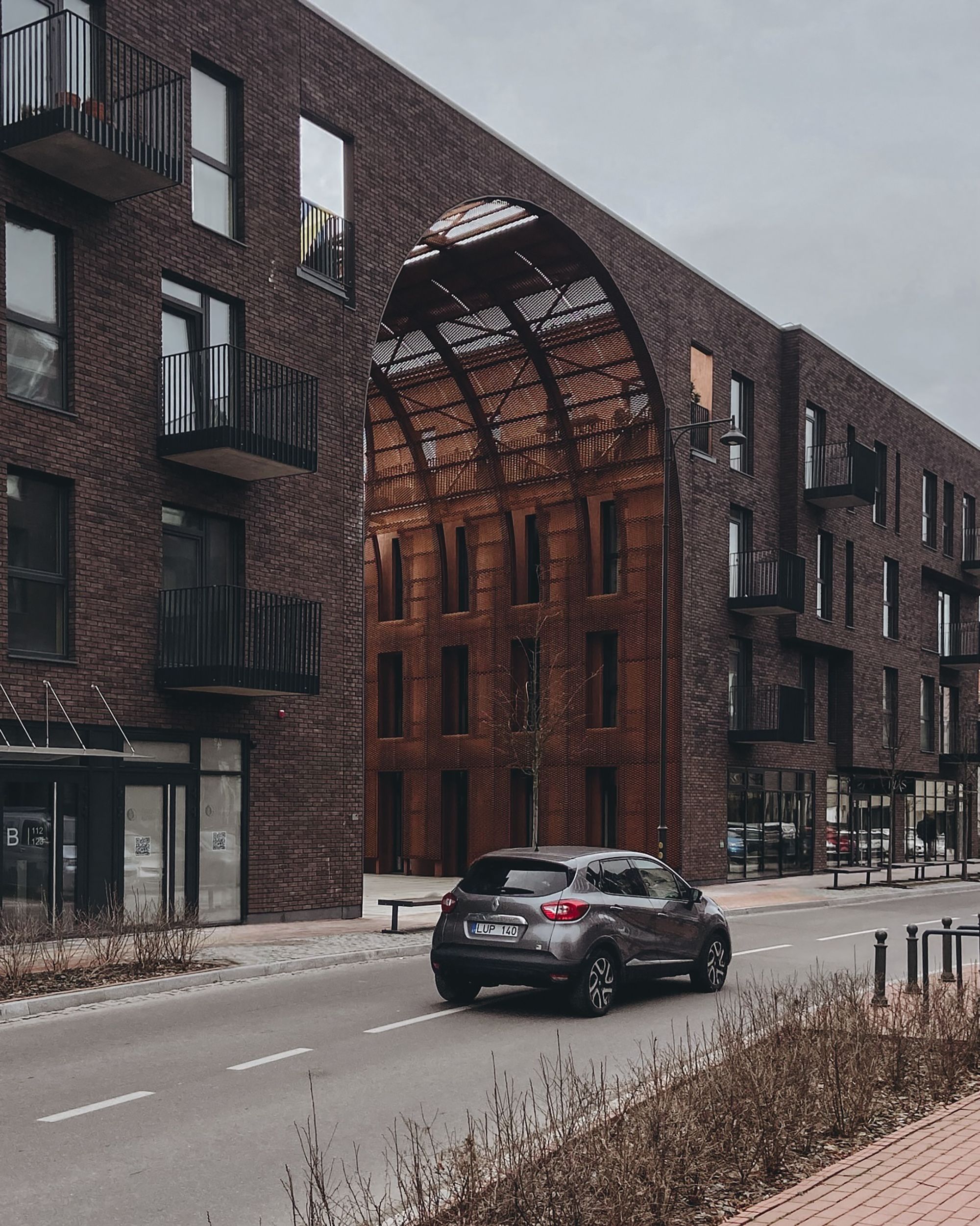 A car drives down a street in front of a brick building · Free Stock Photo