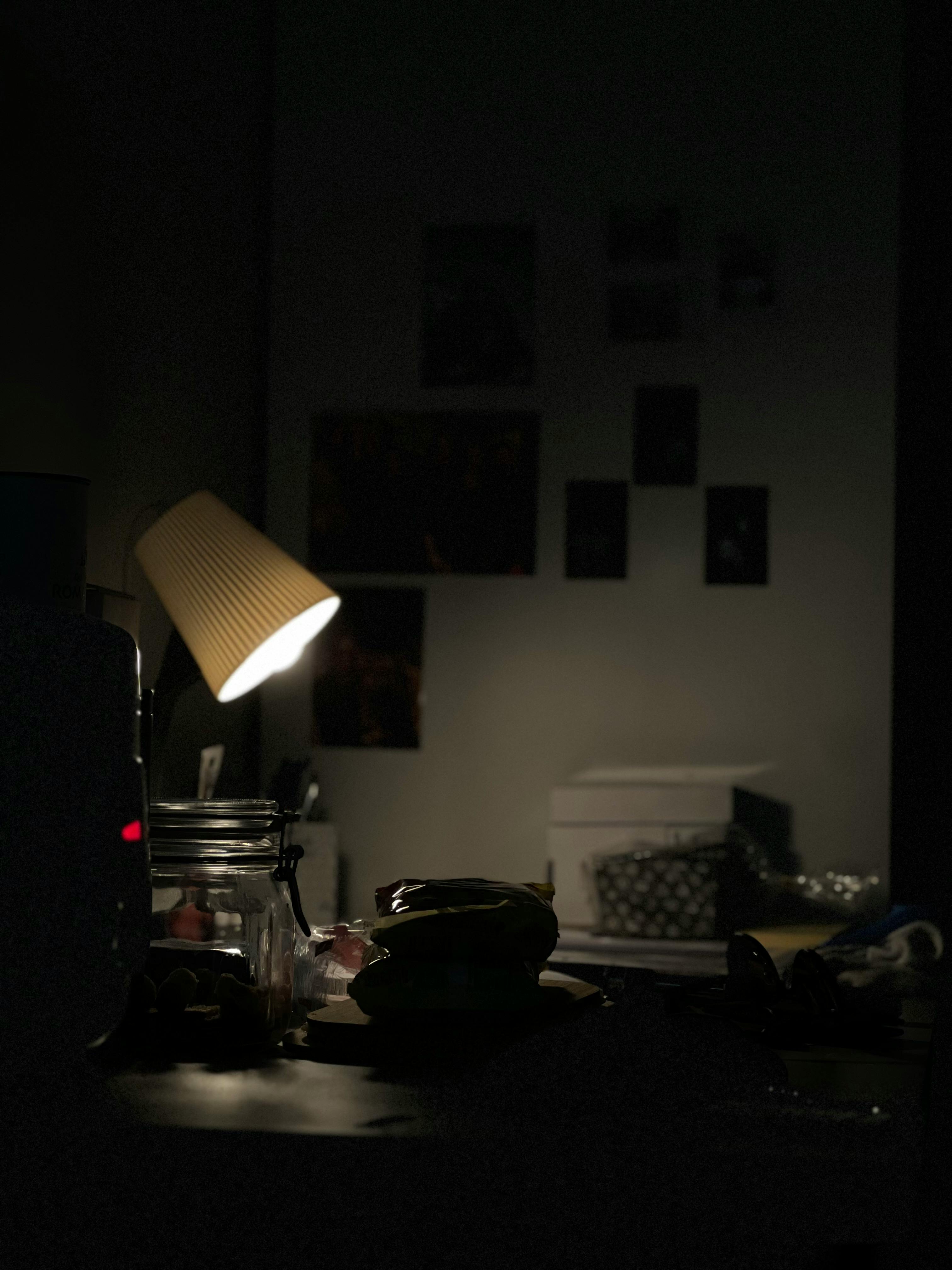 Dark Photo with a Switched on Lamp on a Desk · Free Stock Photo