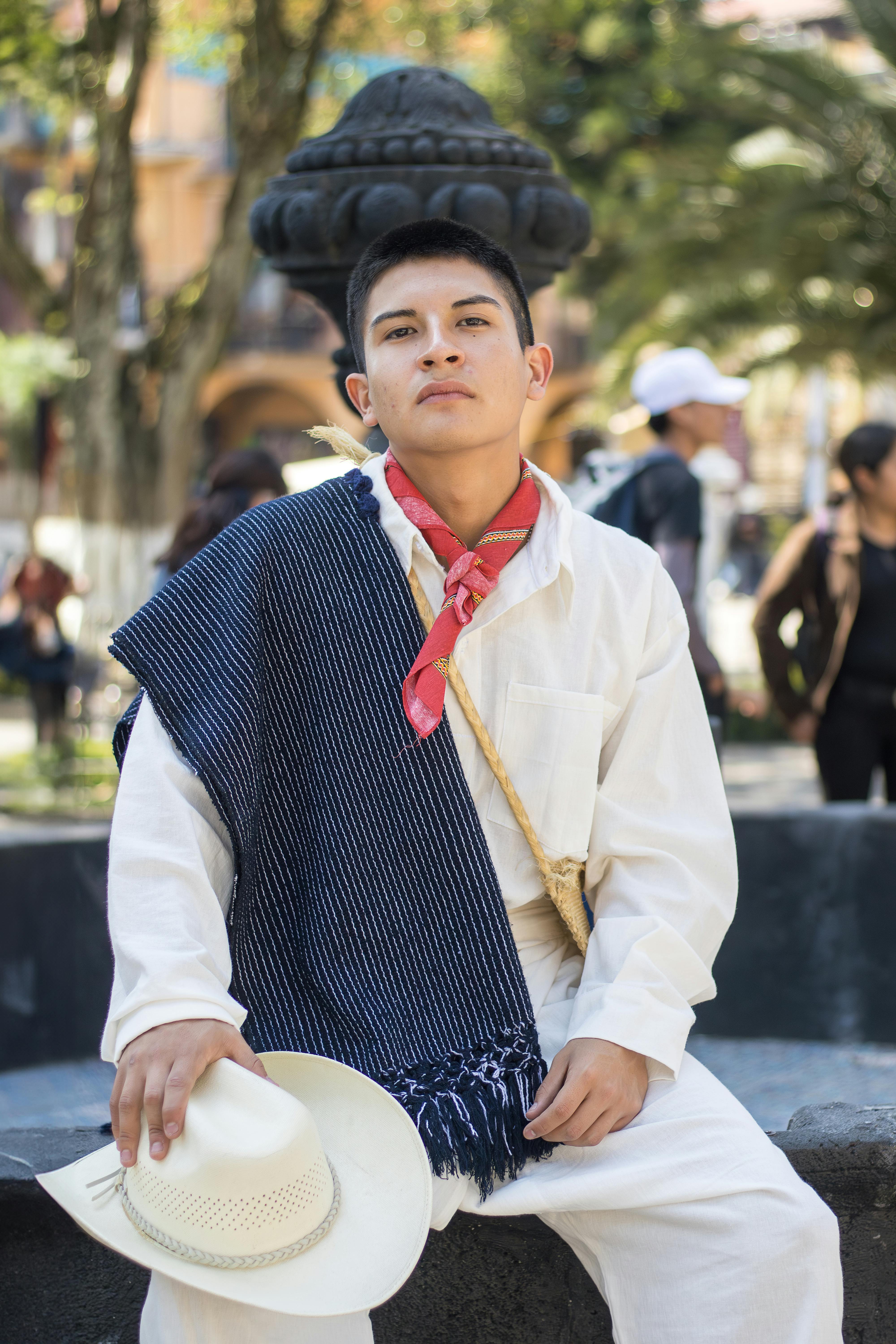 A Boy in Traditional Clothing Sitting in a Park · Free Stock Photo
