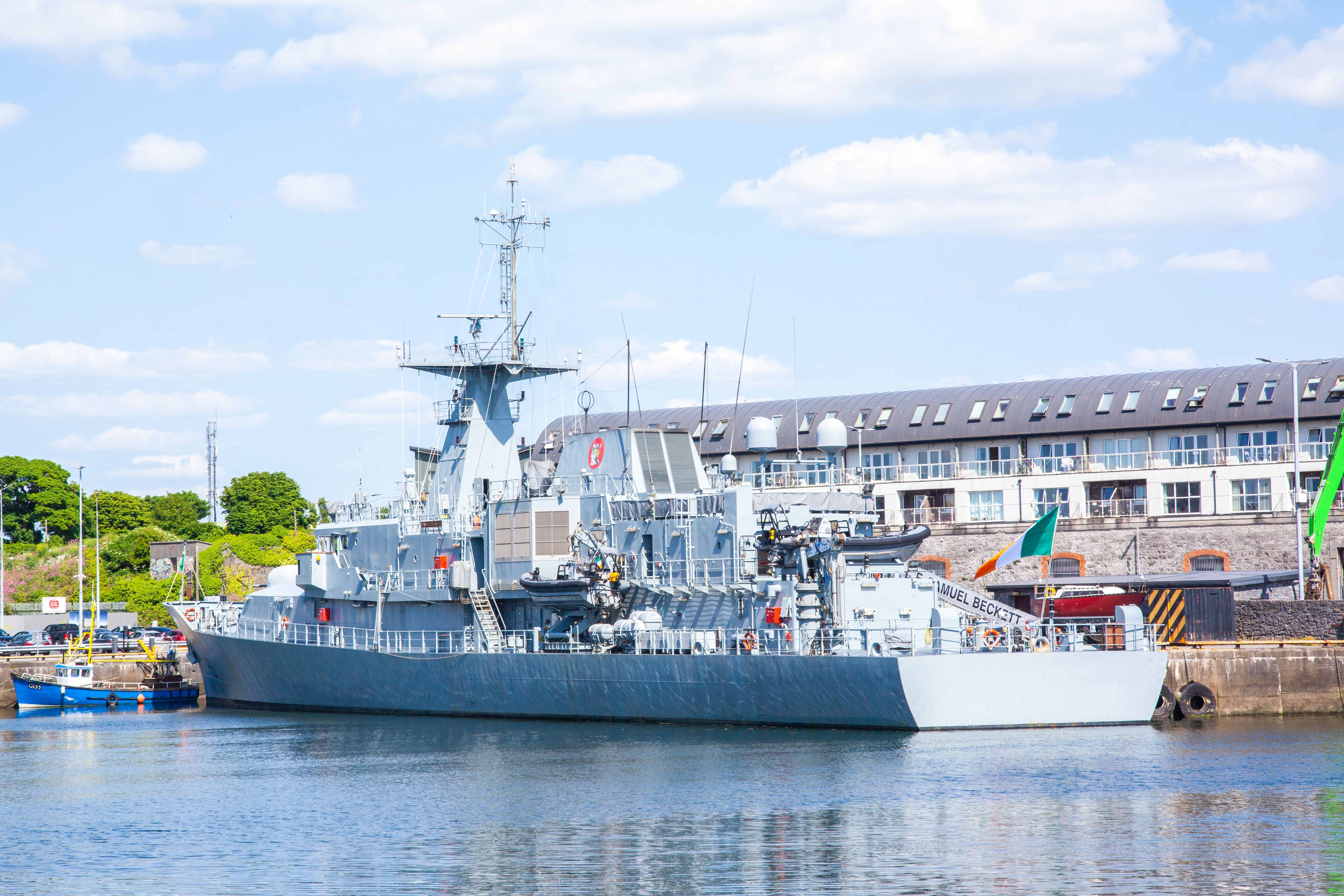 A large navy ship is docked in a harbor · Free Stock Photo