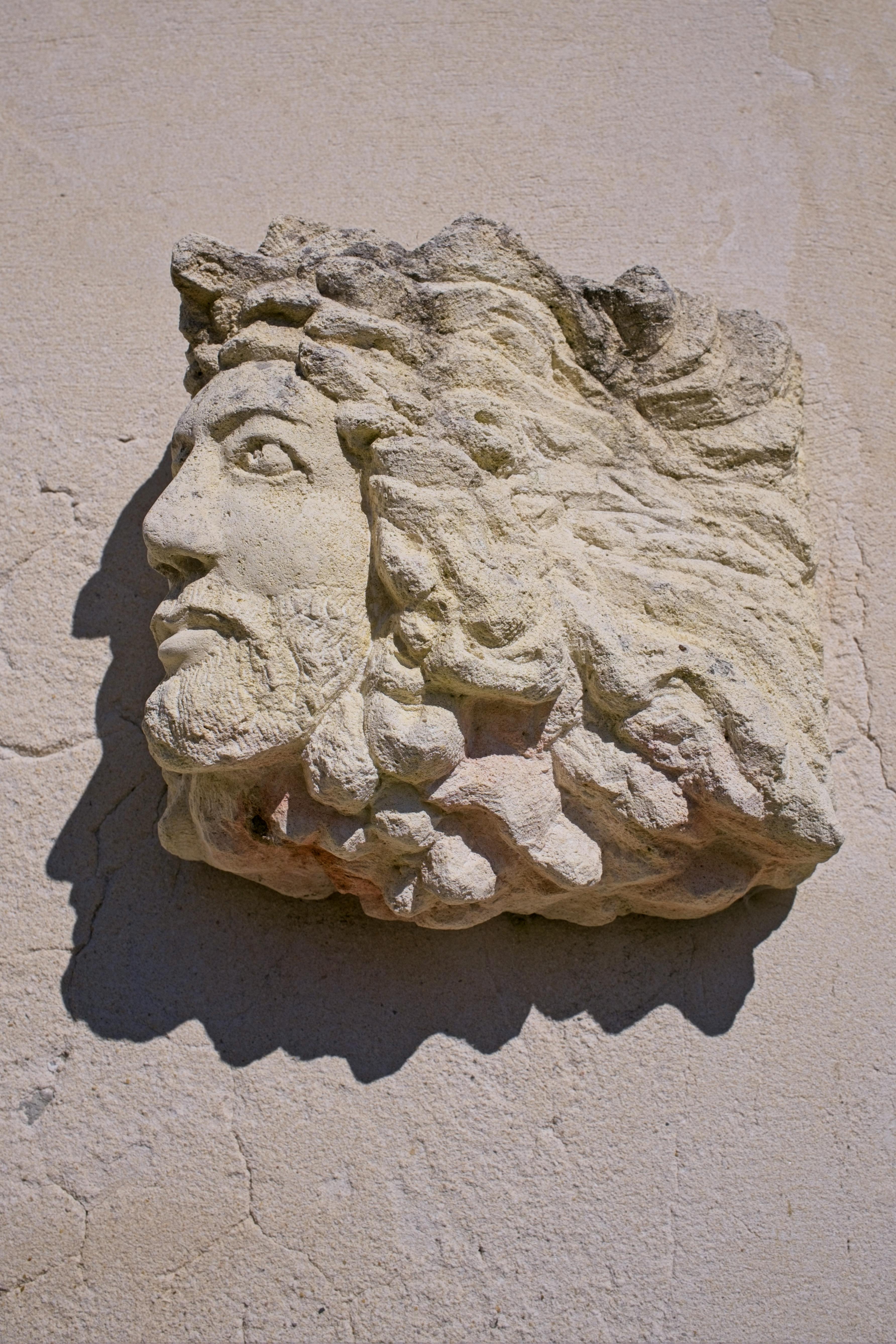 A stone head with a long beard on it · Free Stock Photo