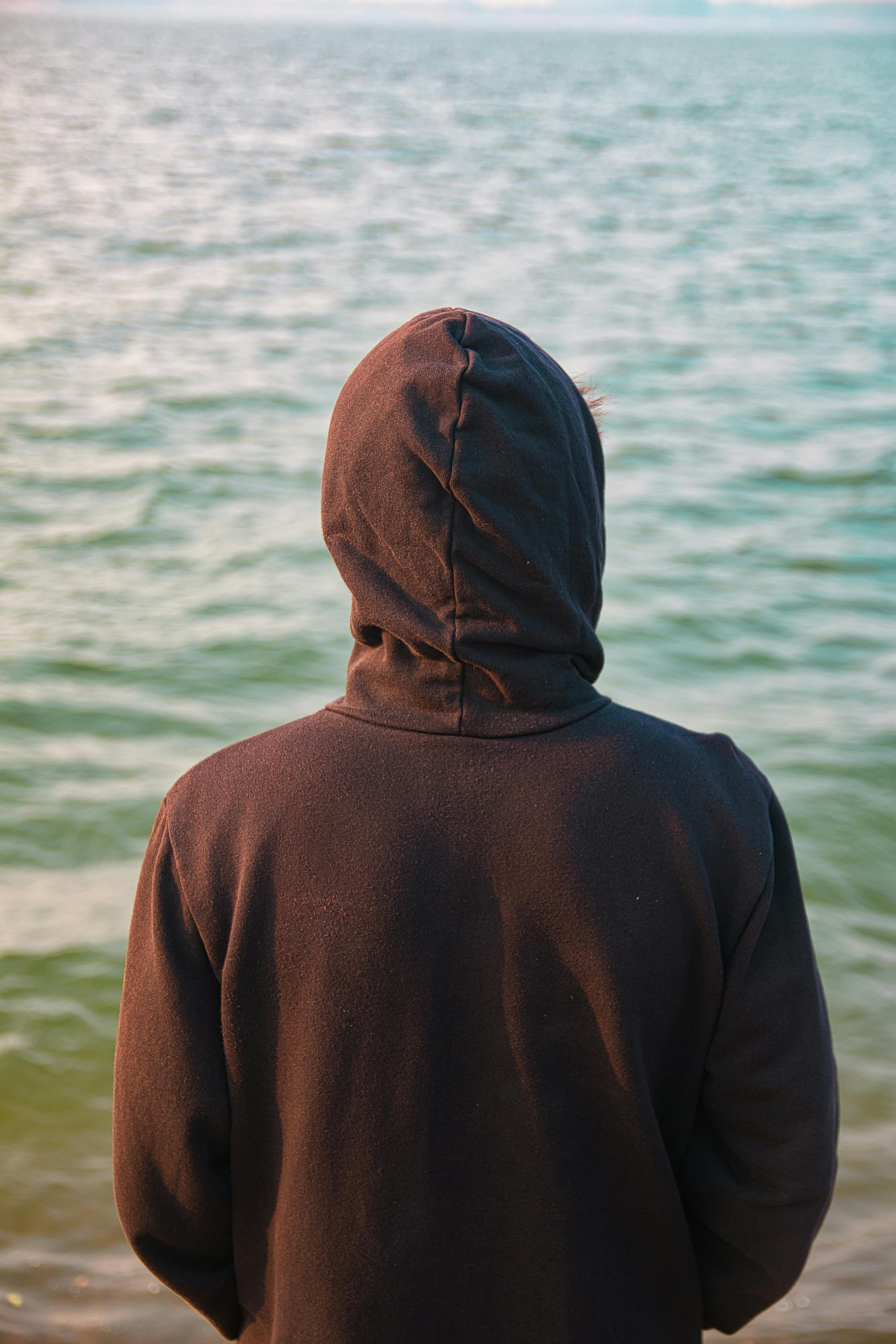Back View of a Person in a Hood at the Seashore · Free Stock Photo