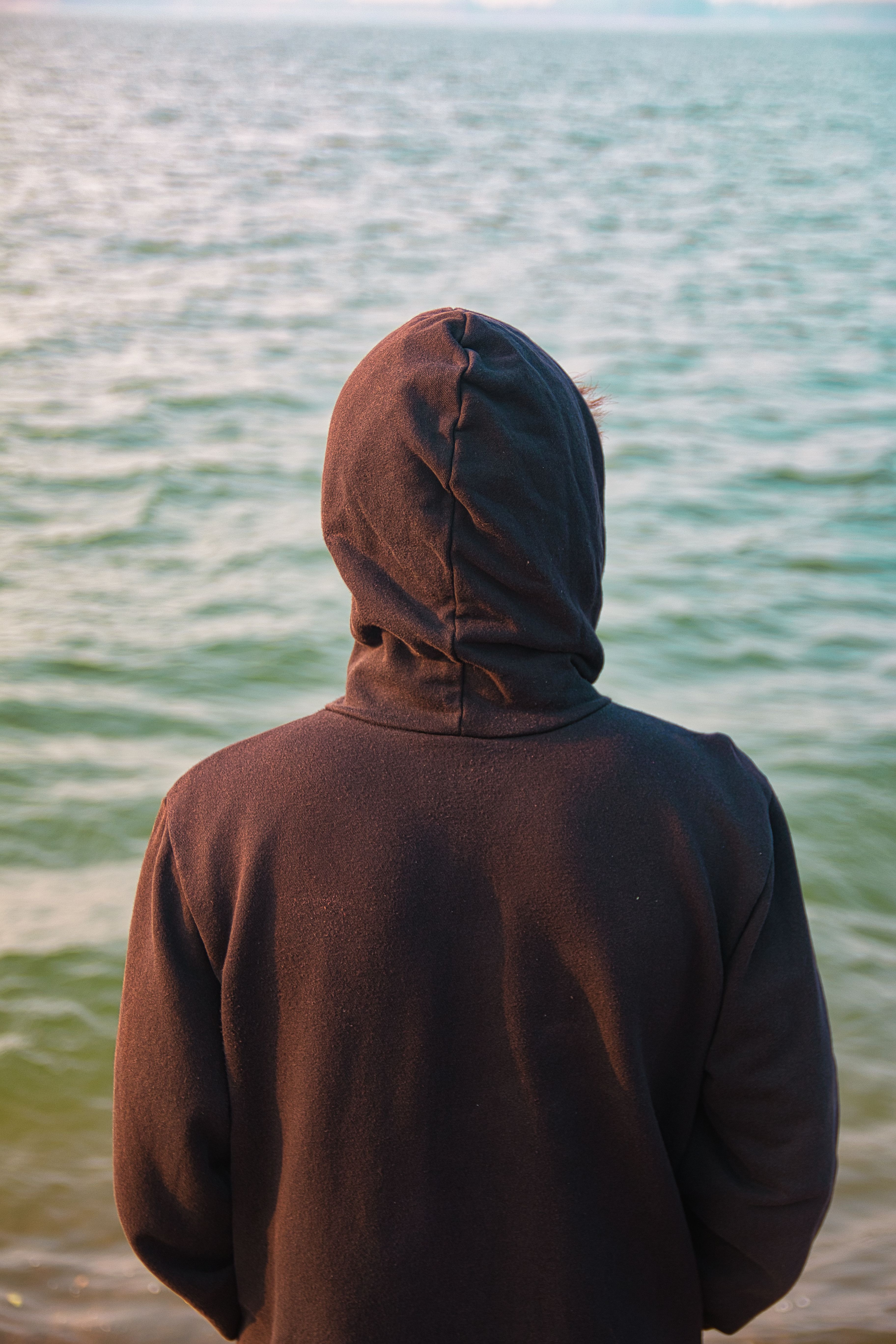 Back View of a Person in a Hood at the Seashore · Free Stock Photo