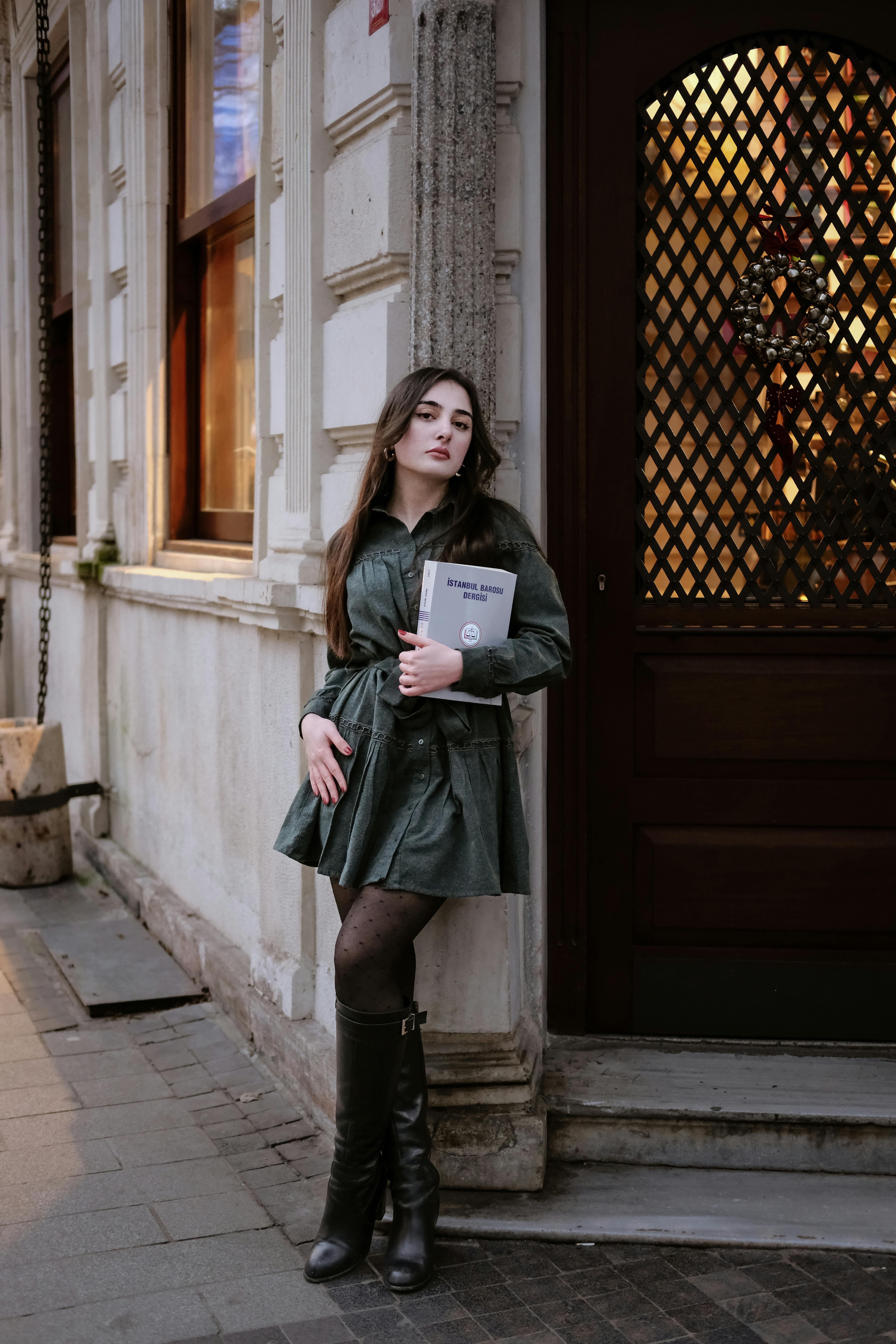 Model Standing with Book by Wall · Free Stock Photo