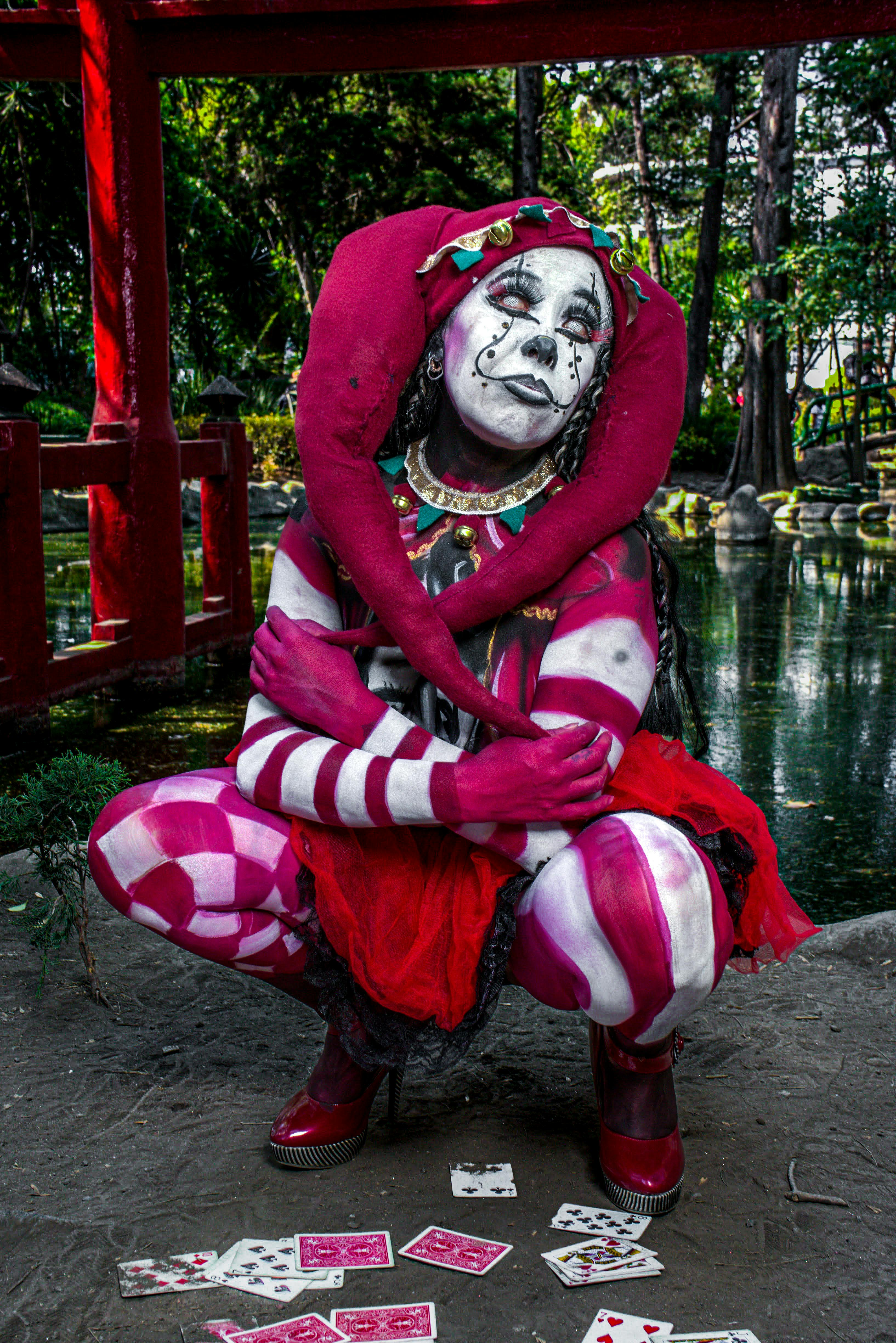 A woman dressed in clown makeup sitting on a bench · Free Stock Photo