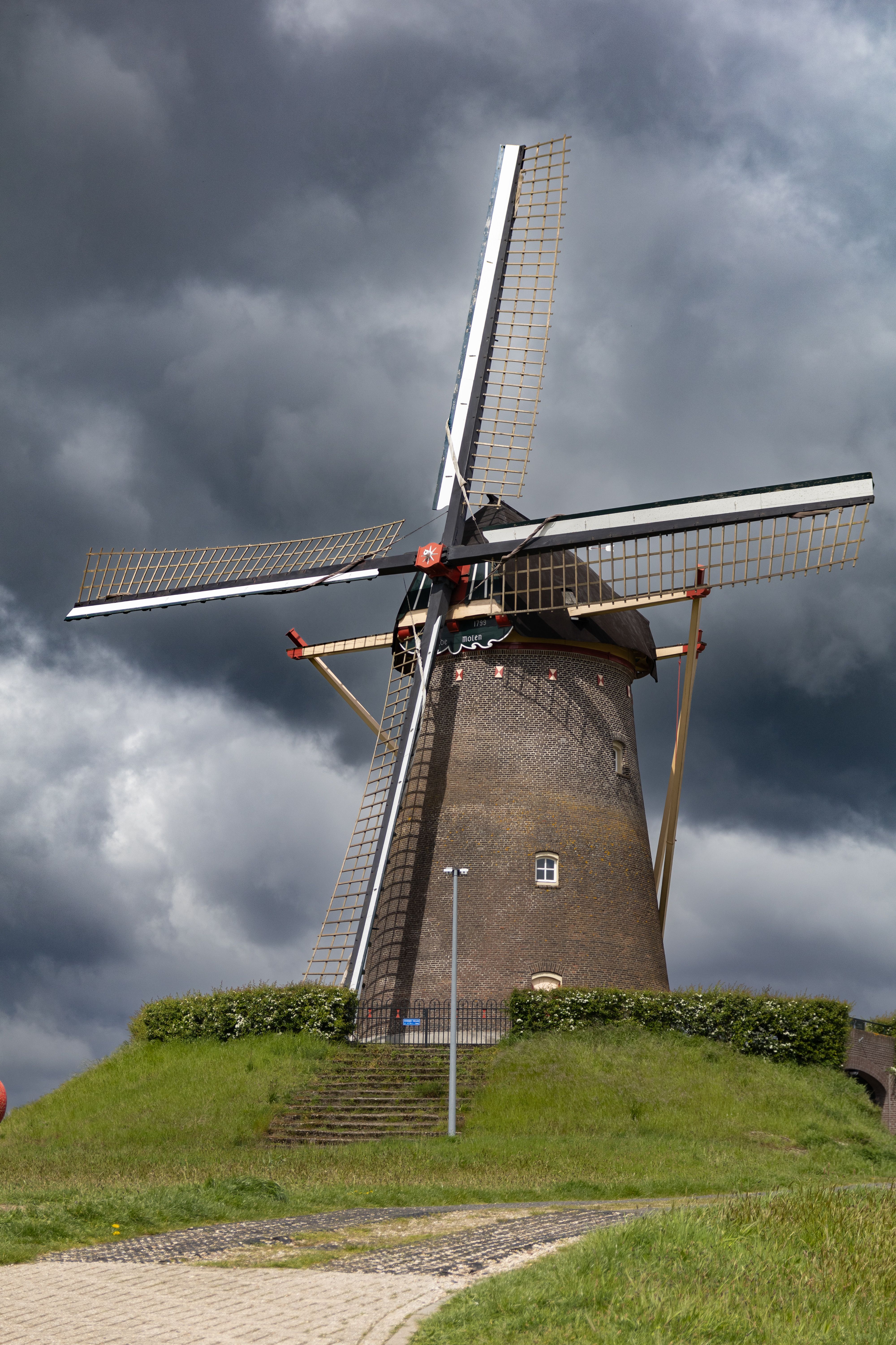 A Dutch windmill on top of a hill, with a paved path leading to it ...