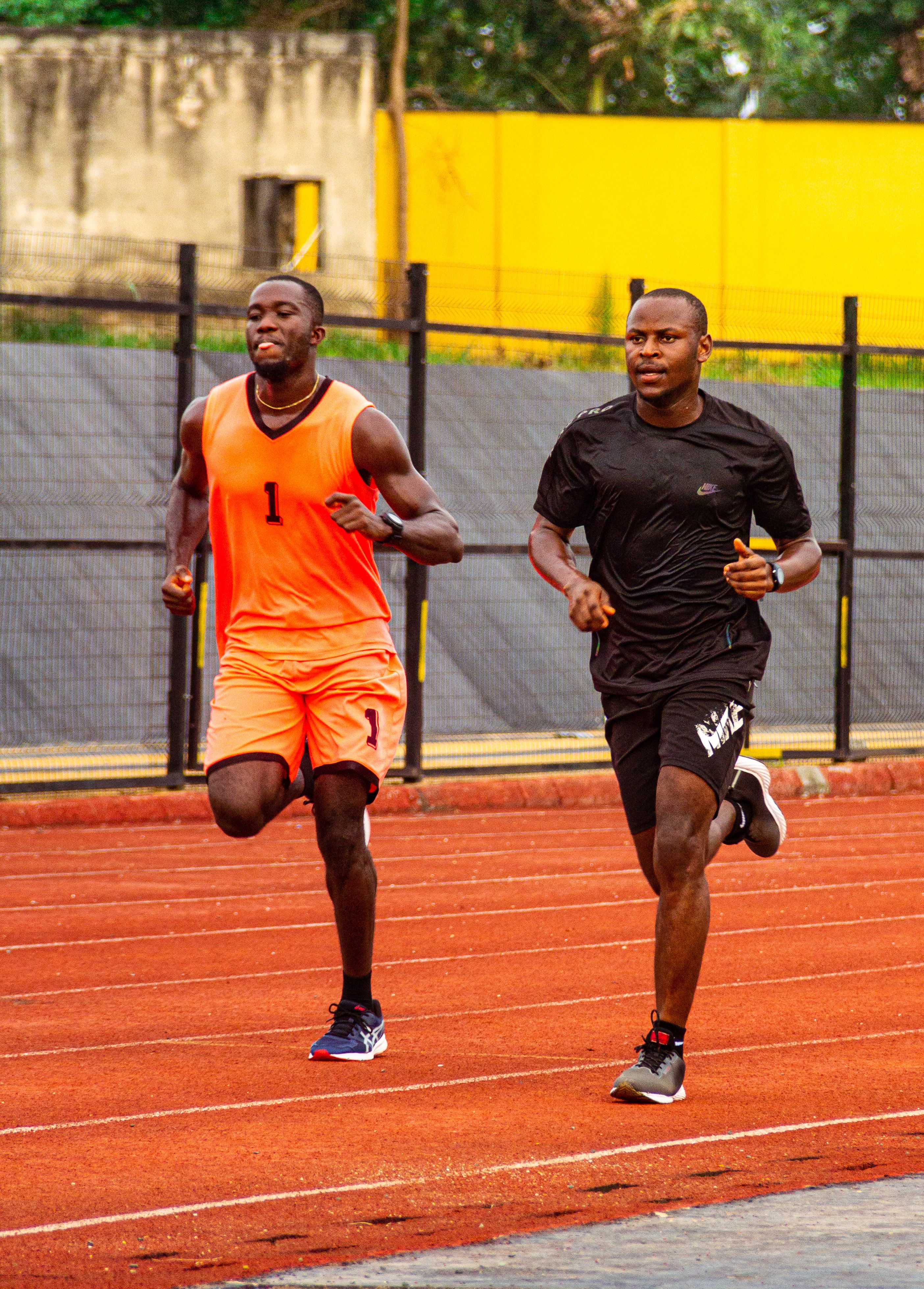 Two men running on a track with a ball · Free Stock Photo
