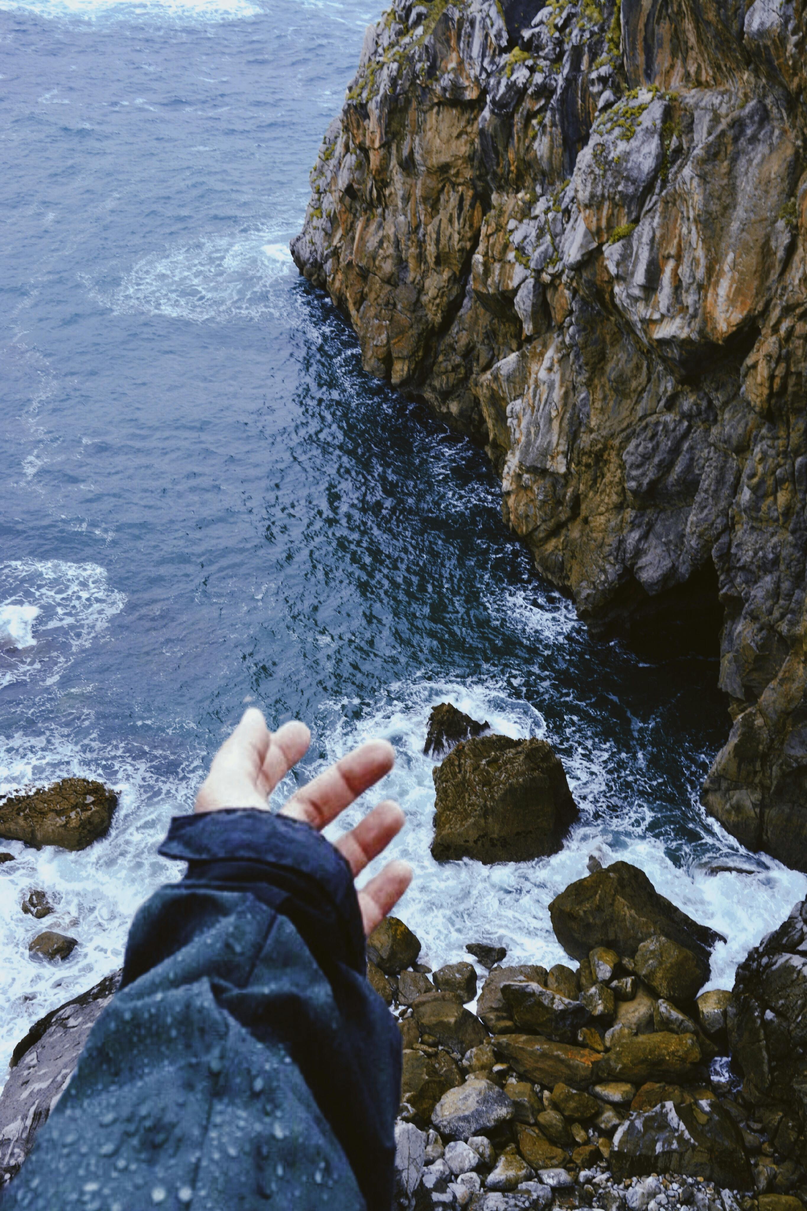 Person Standing On Rock Cliff Facing The Sea · Free Stock Photo