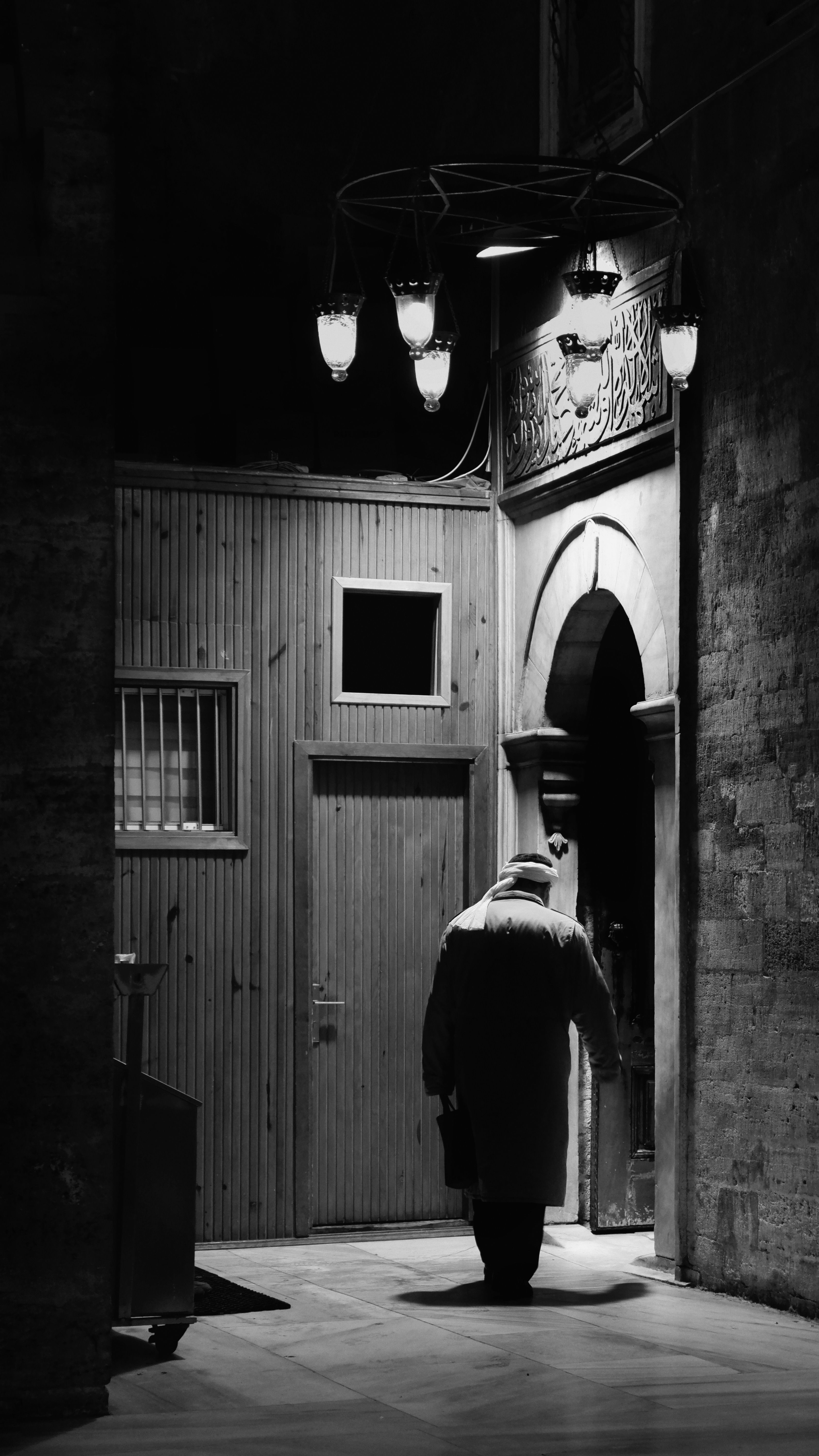 Black and White Photo of a Man Walking into a Building · Free Stock Photo