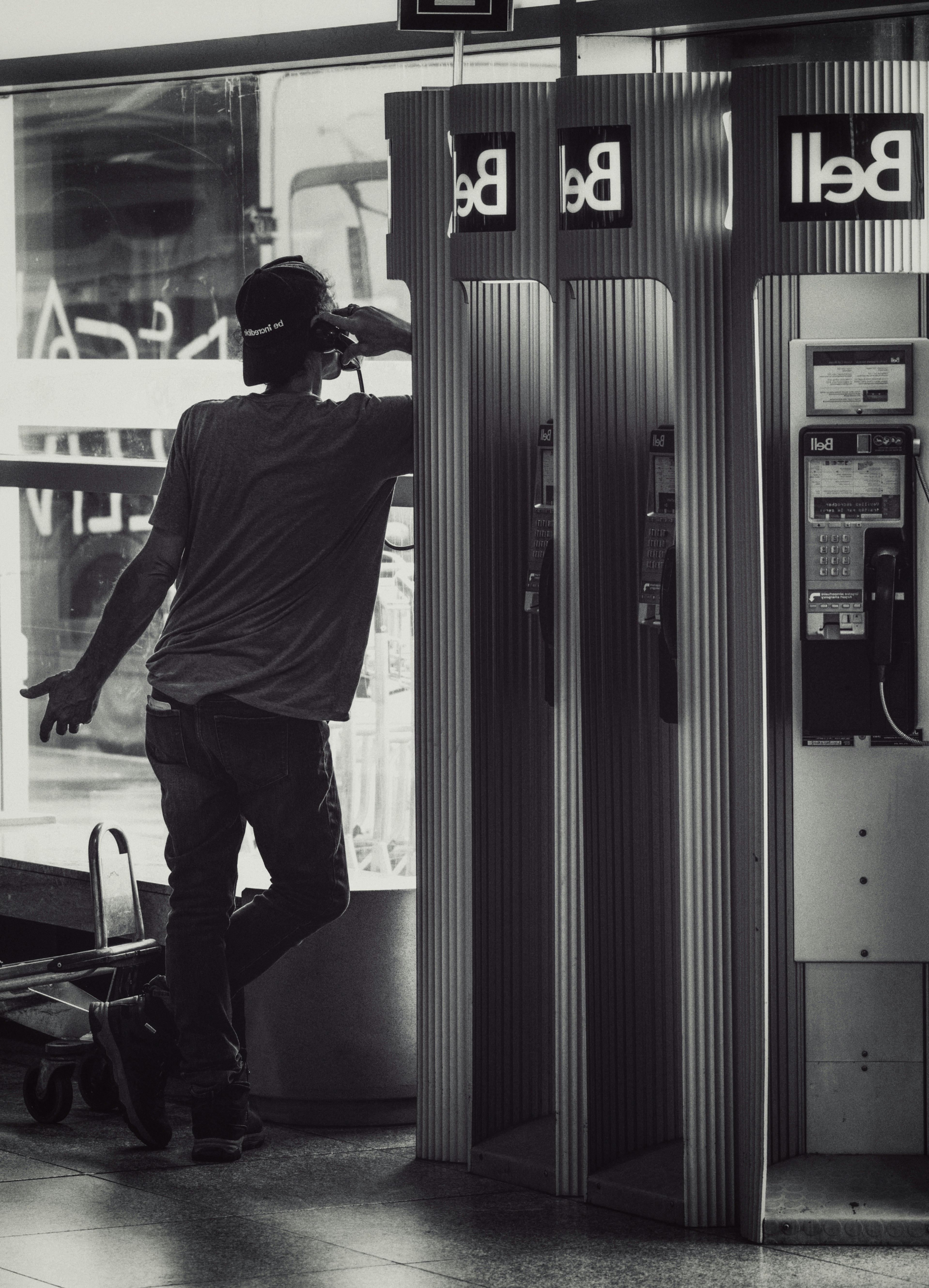 Back View of a Man Using a Payphone in a City · Free Stock Photo