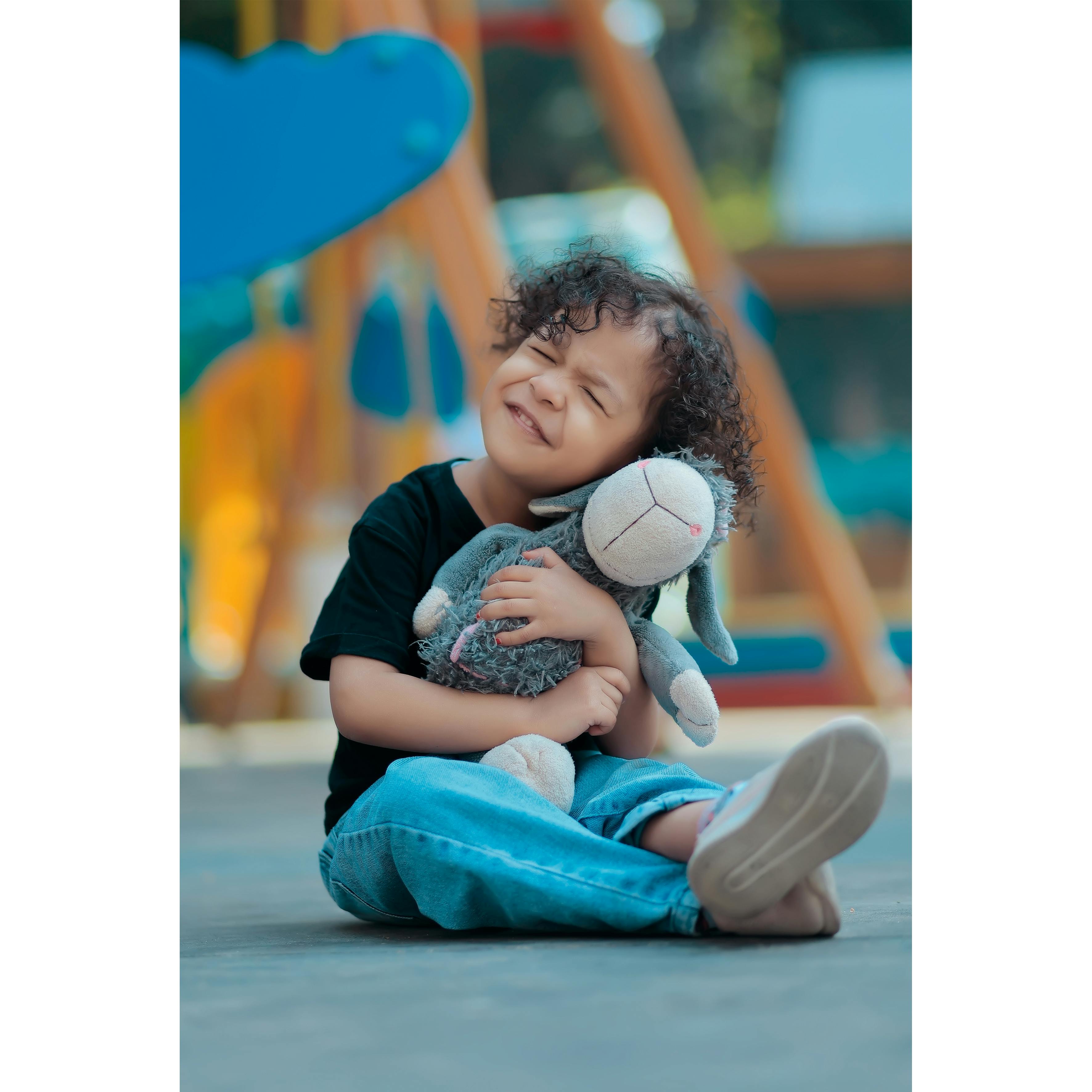 Adorable Boy Hugging a Plushie on the Playground · Free Stock Photo