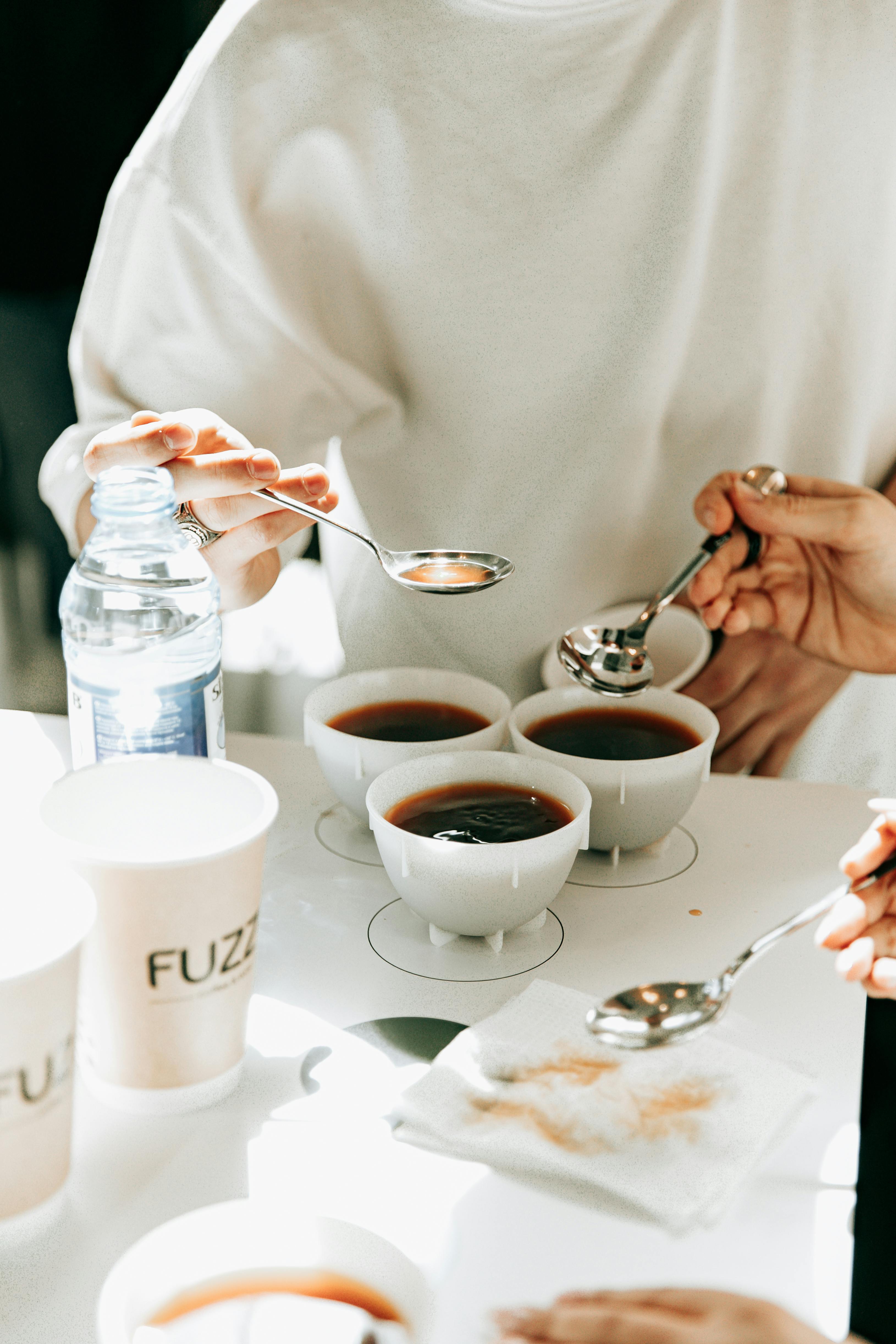 Hands with Teaspoons over Coffee on Table · Free Stock Photo