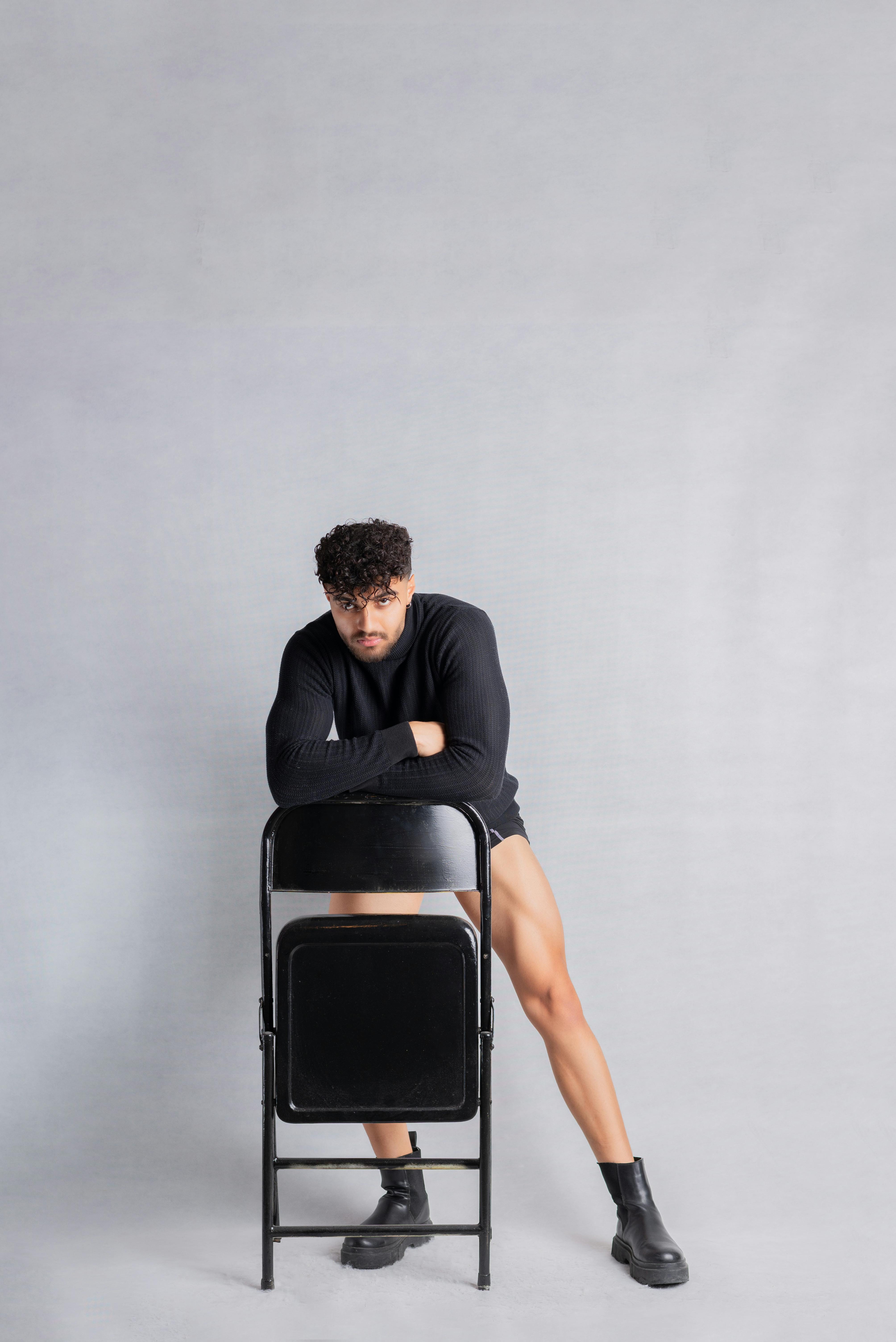 Handsome Man Leaning Against Black Chair · Free Stock Photo