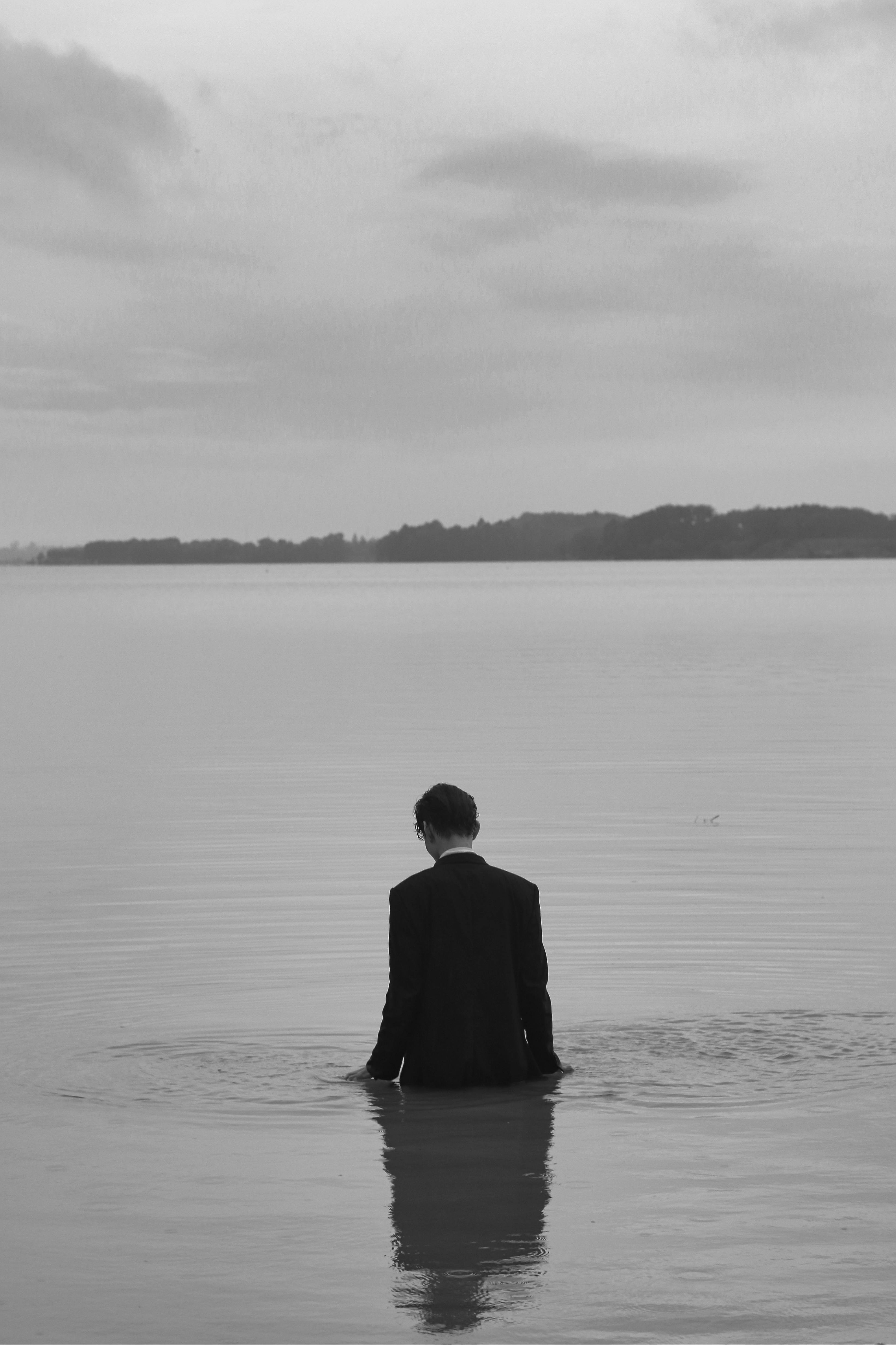 Man in a Suit Standing Waist-deep in a Lake and Looking into the Water ...