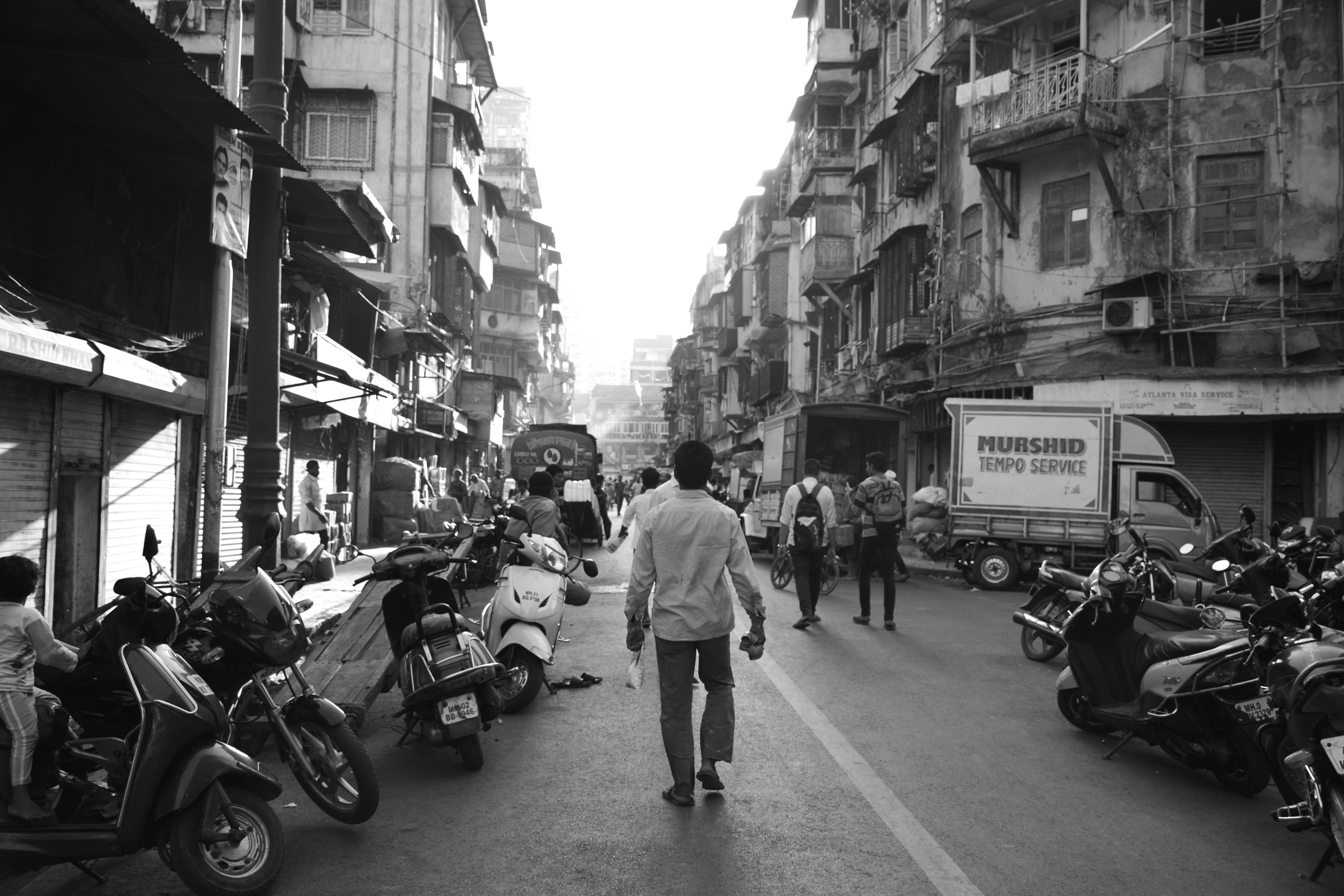 Man Walking among Motor Scooters on Street · Free Stock Photo