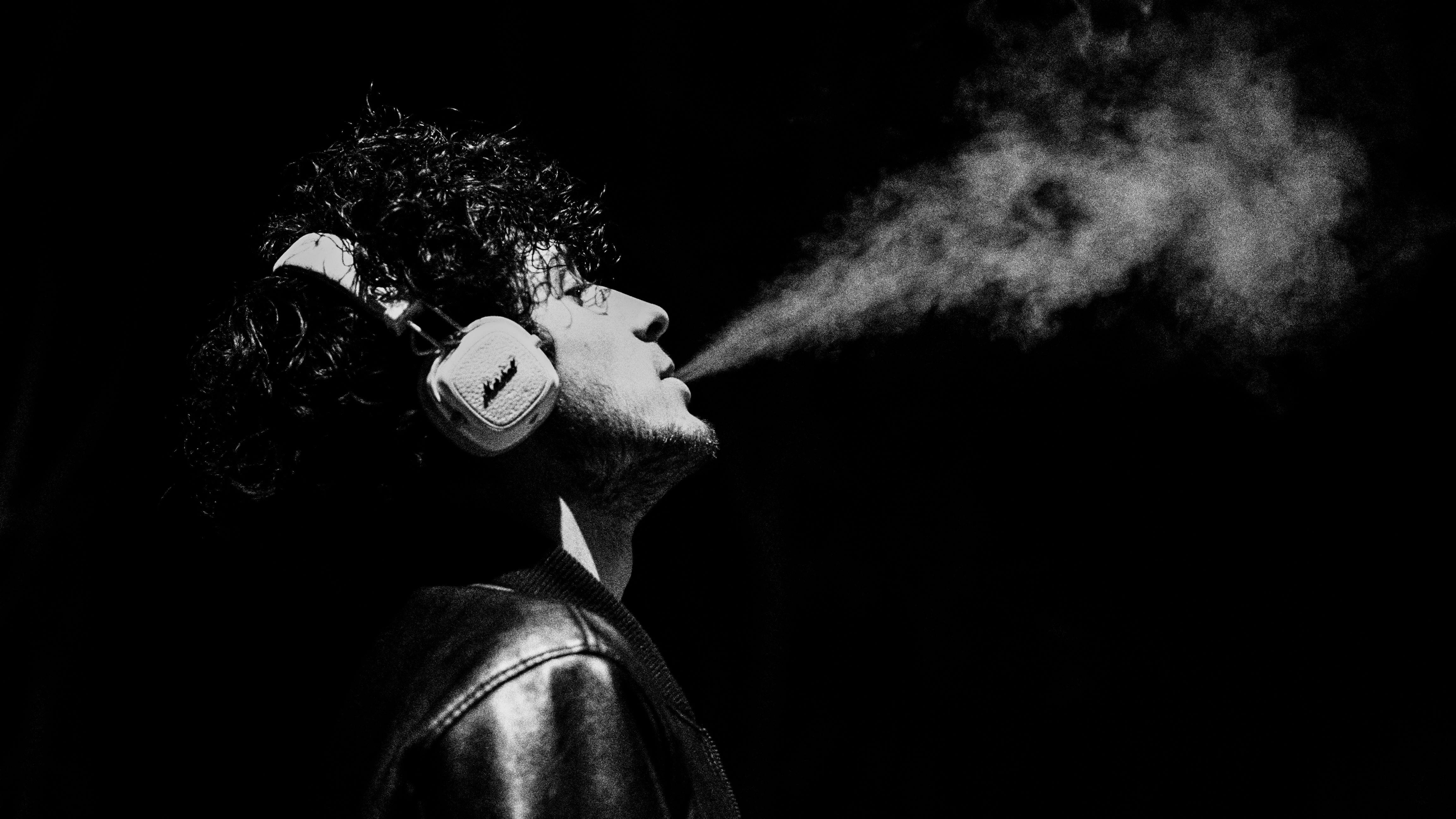 A man with headphones smoking a cigarette · Free Stock Photo