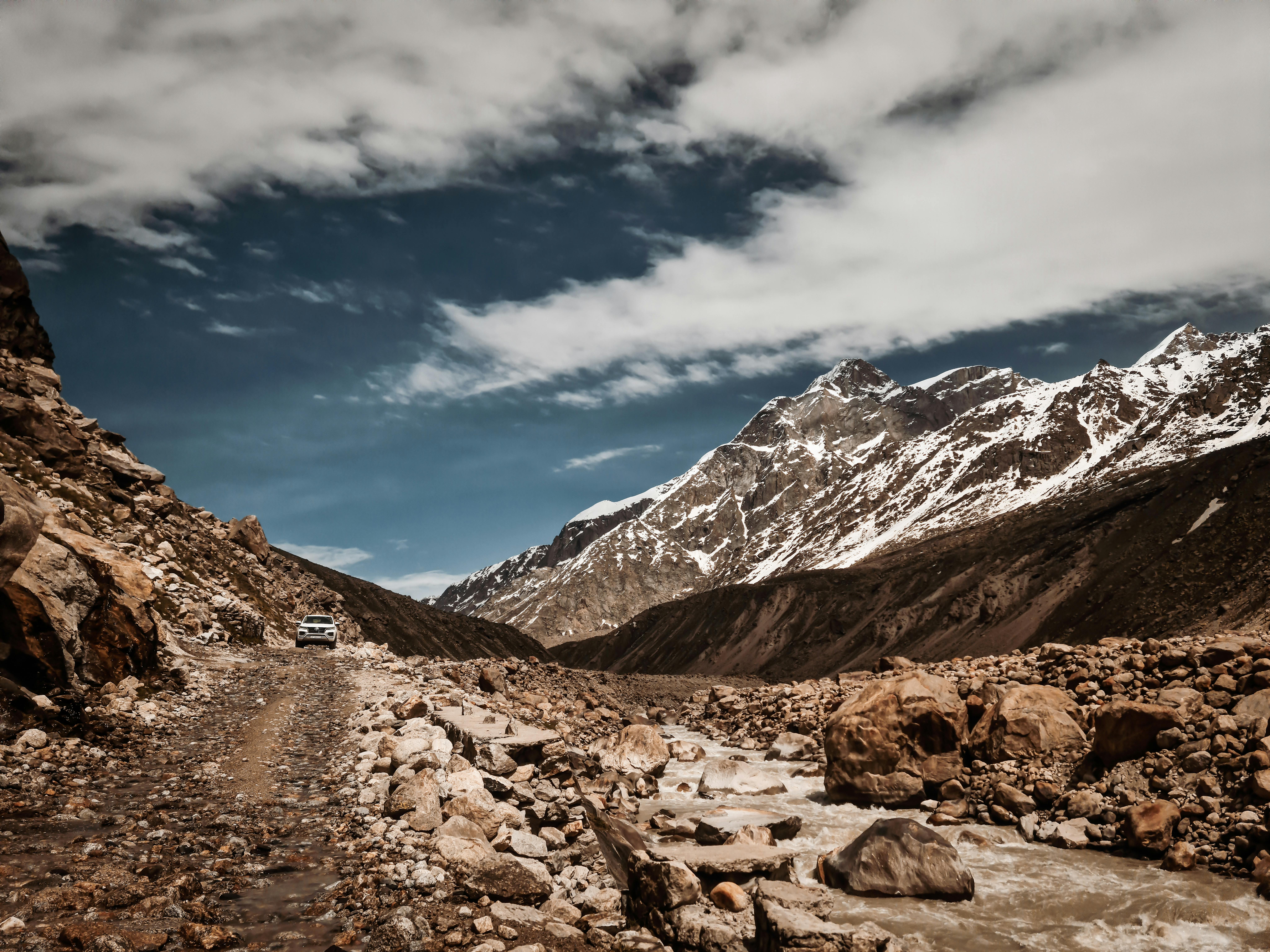 A Car Driving in the Distance in Rocky Mountains · Free Stock Photo
