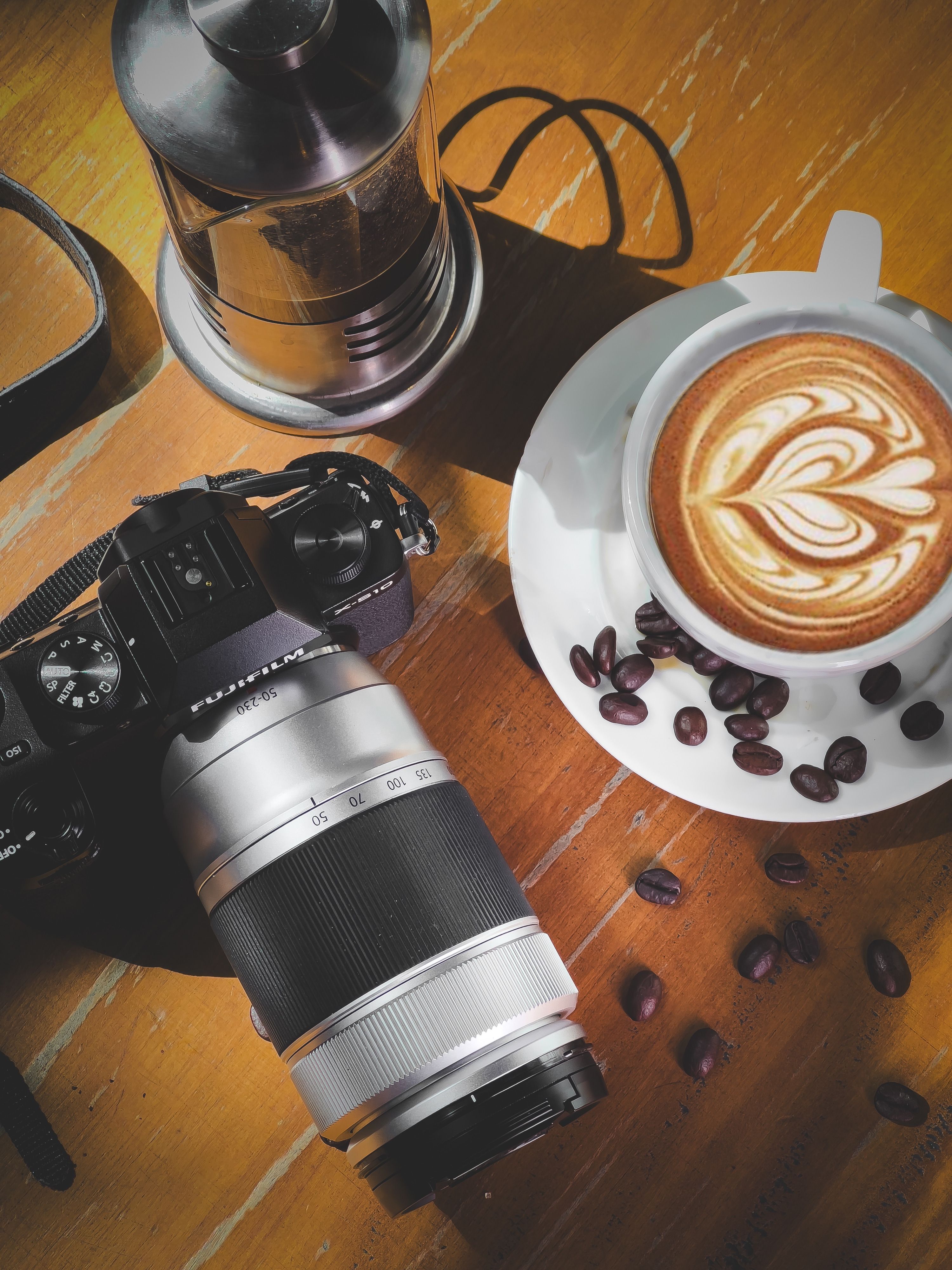 A camera and coffee on a table with a cup of coffee · Free Stock Photo