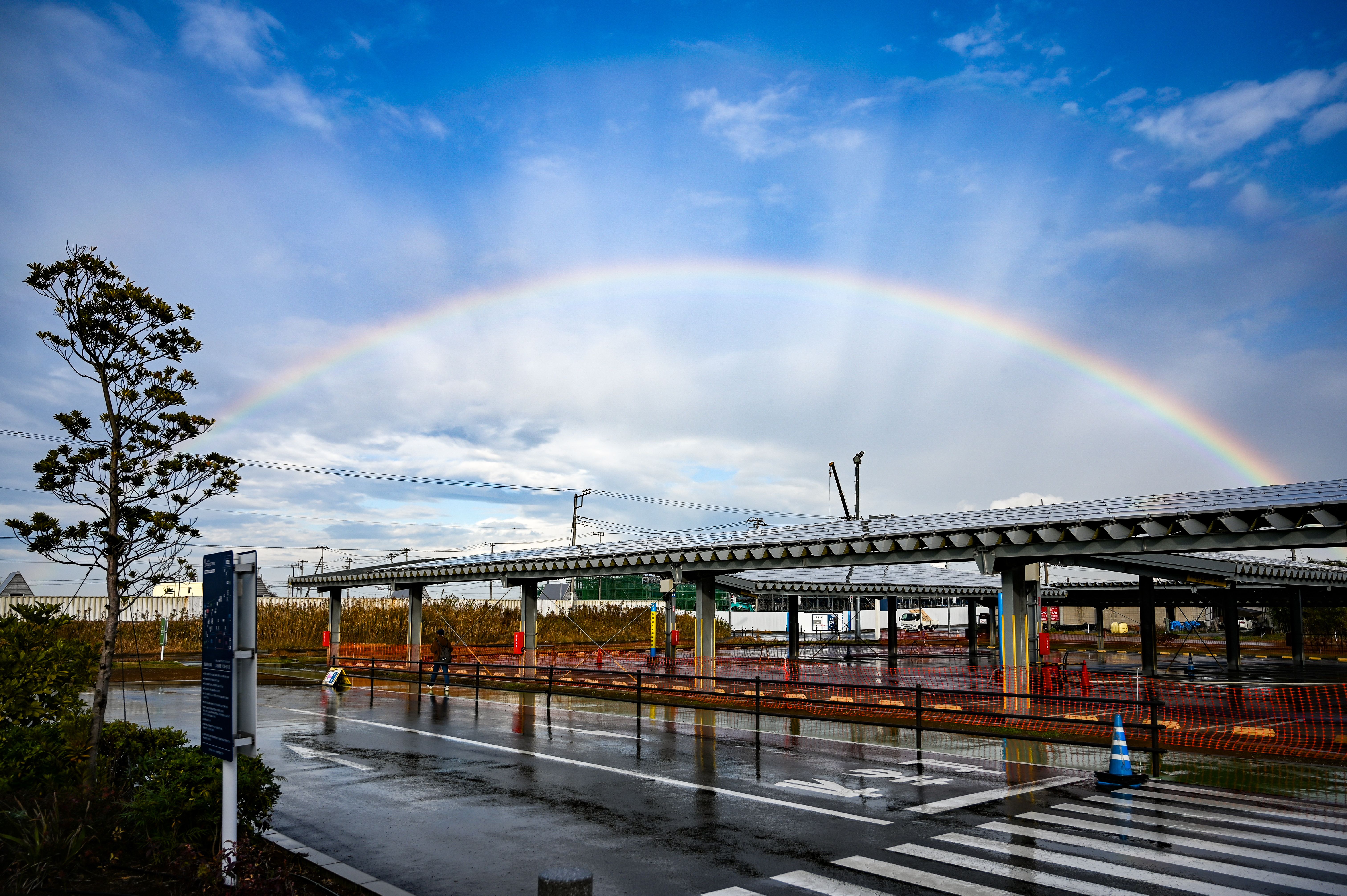 A rainbow is seen over a highway and train station · Free Stock Photo