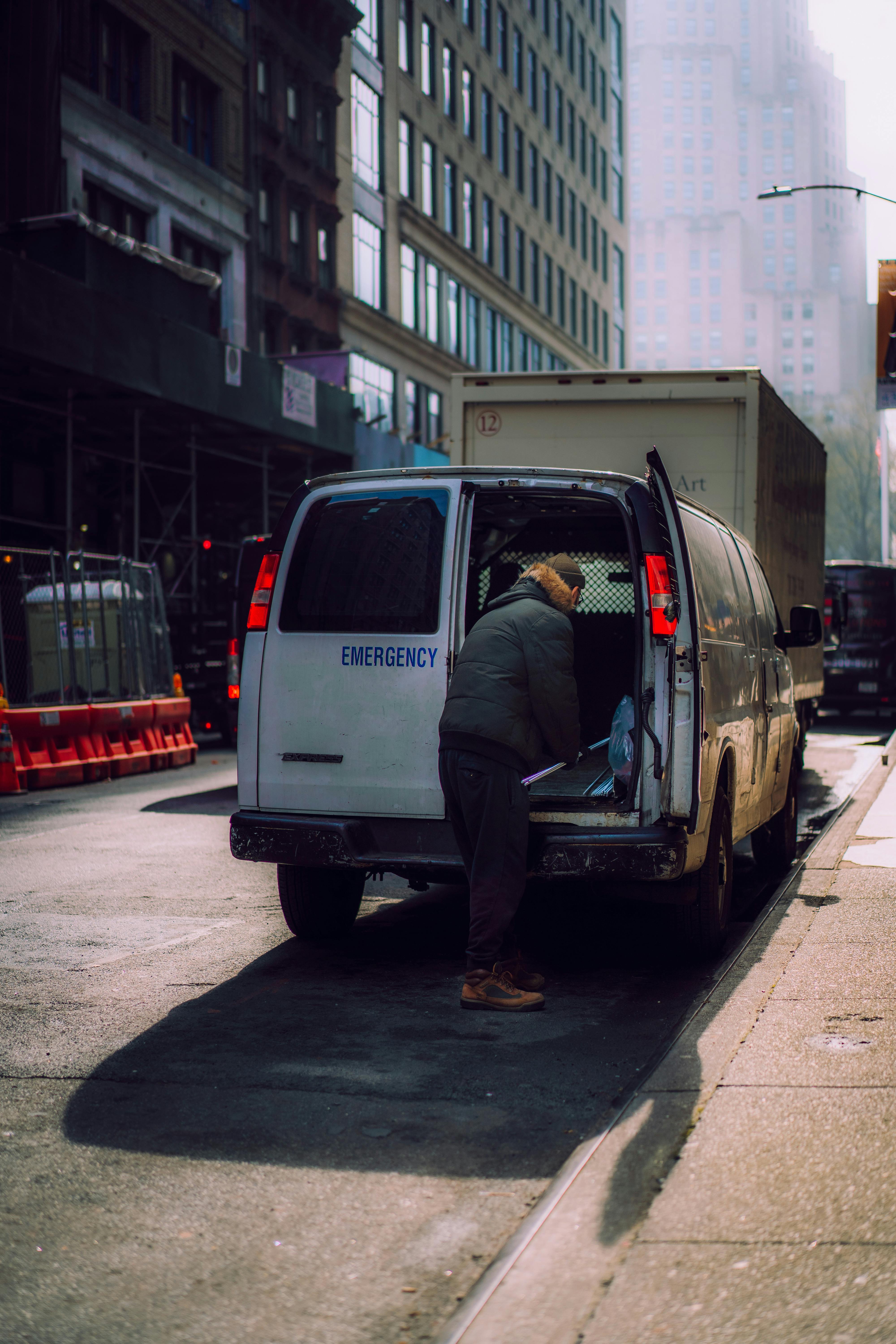 A Man Standing by His Van Parked on a Street in a City · Free Stock Photo
