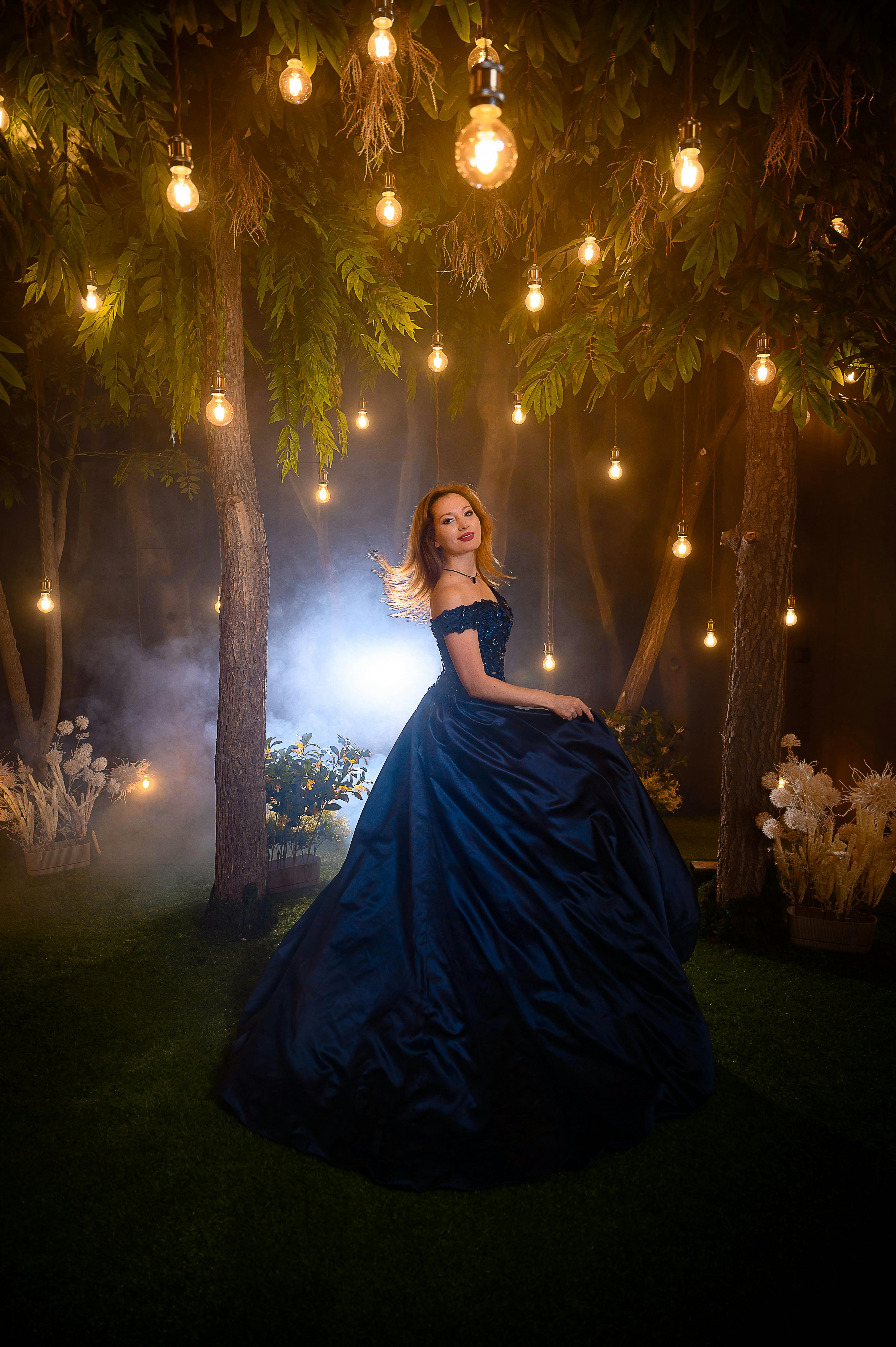A Woman in a Gown Dancing around Trees with Lights · Free Stock Photo