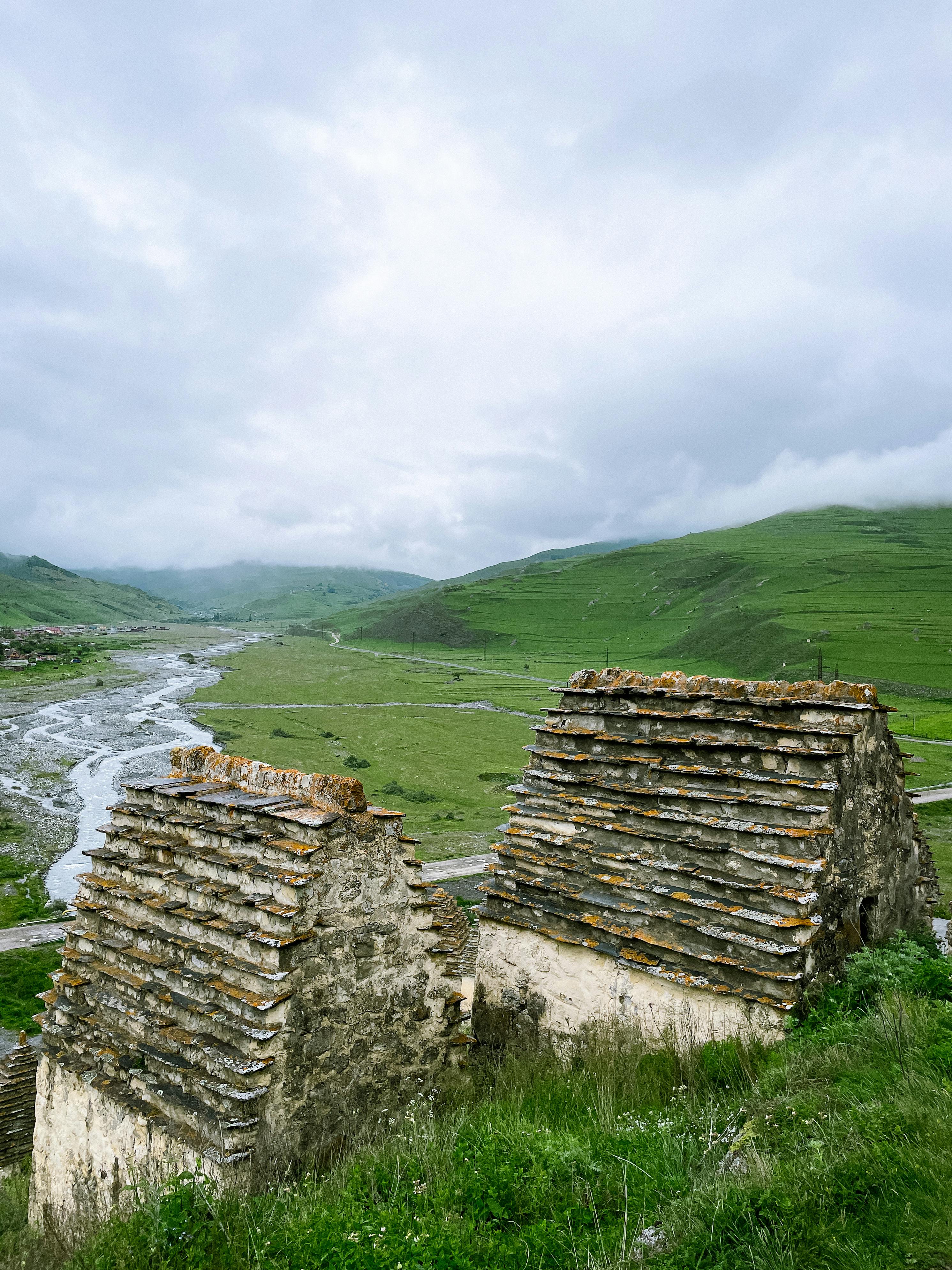 Two stone buildings sit on a hillside overlooking a river · Free Stock ...