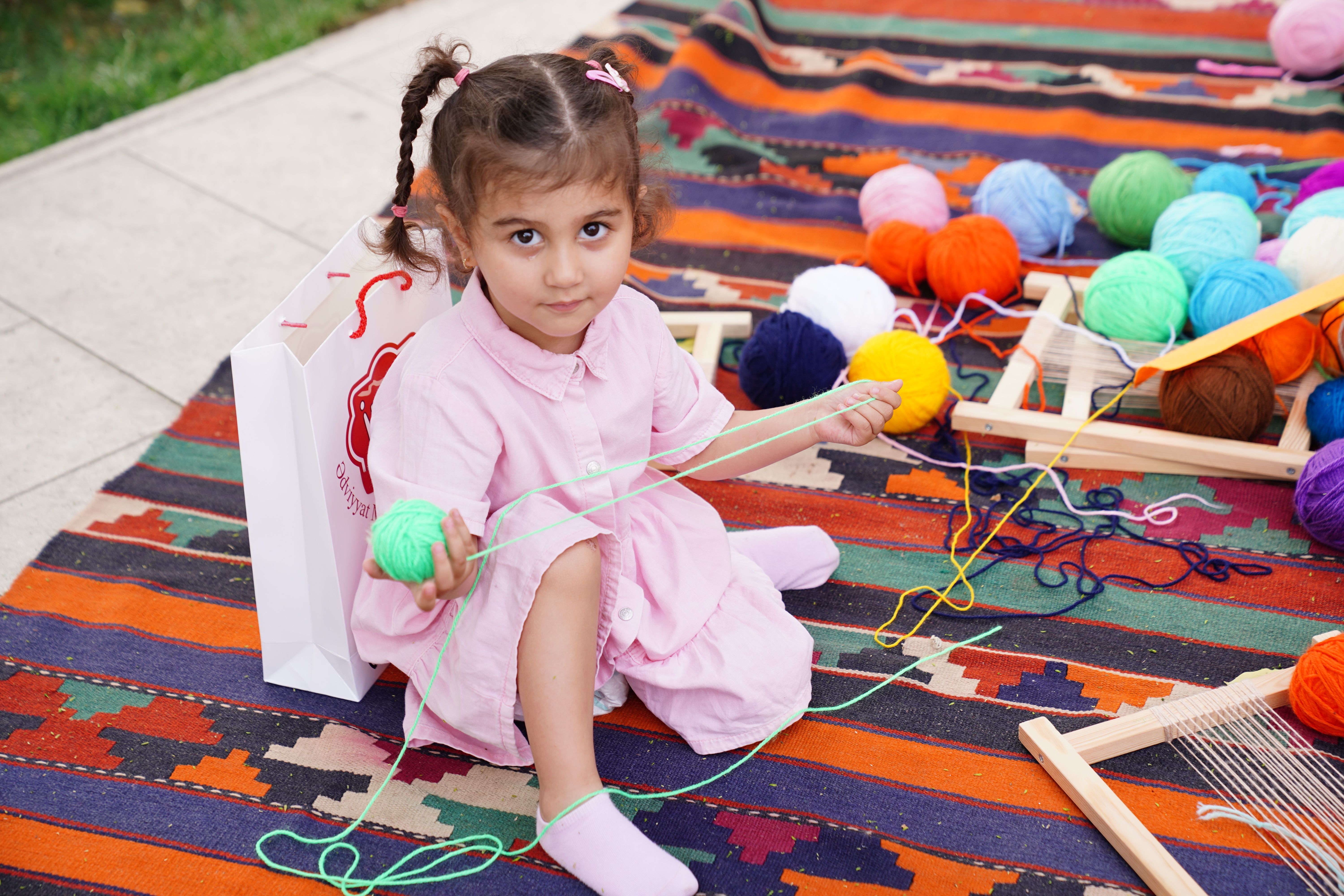 A little girl sitting on a rug with yarn and knitting needles · Free ...