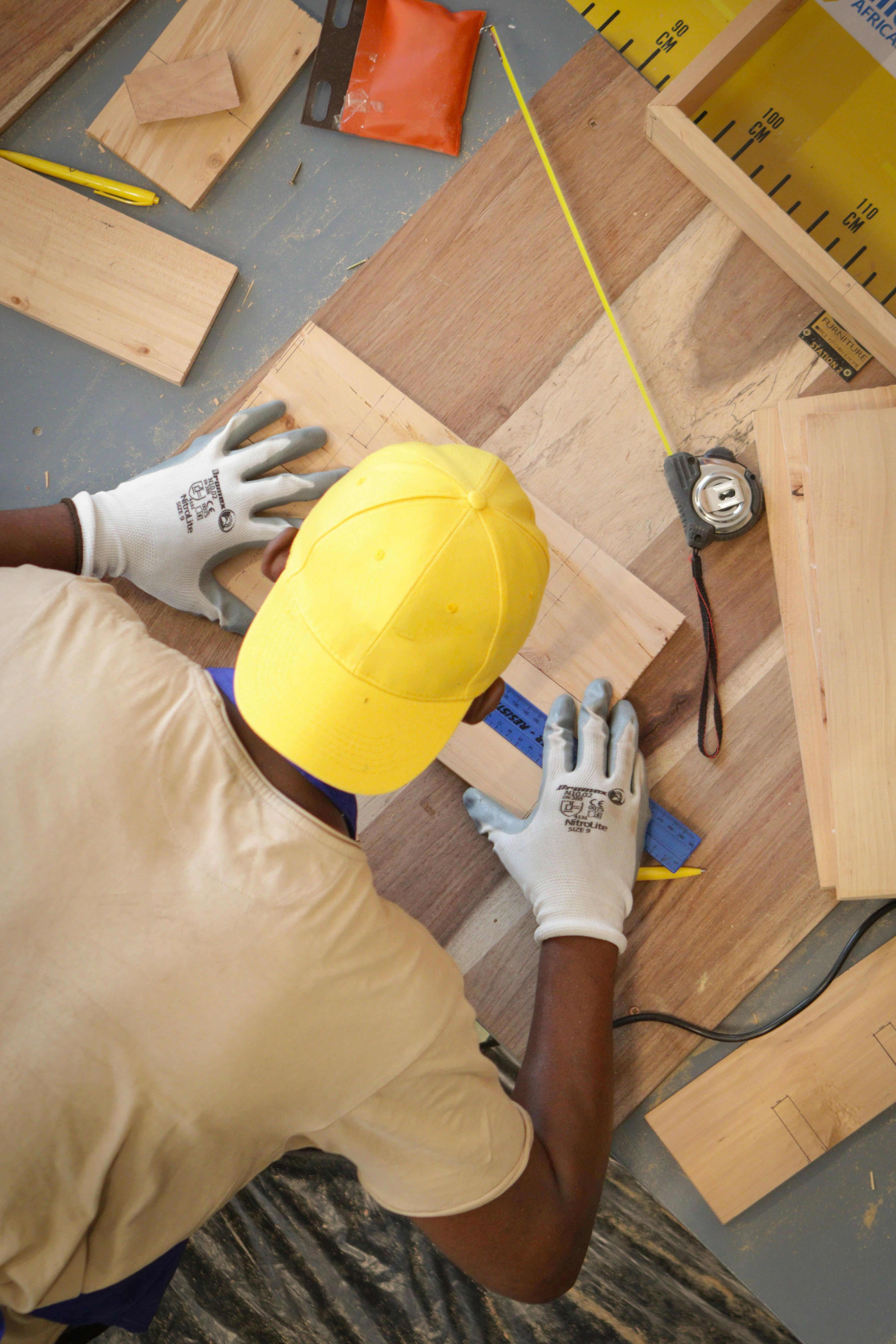 Man measuring wooden plank with measurement tape · Free Stock Photo