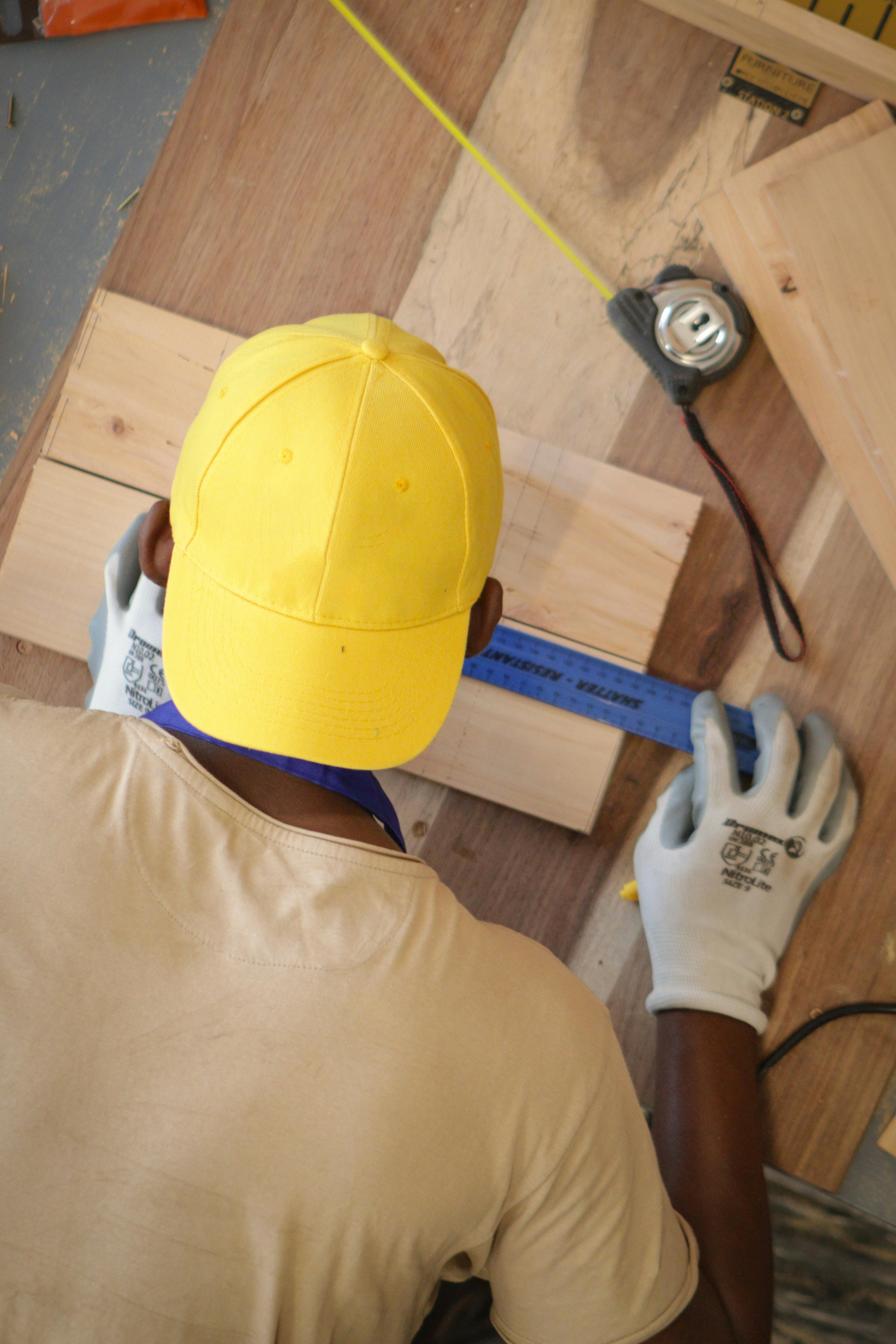 A Man Measuring a Wooden Board · Free Stock Photo